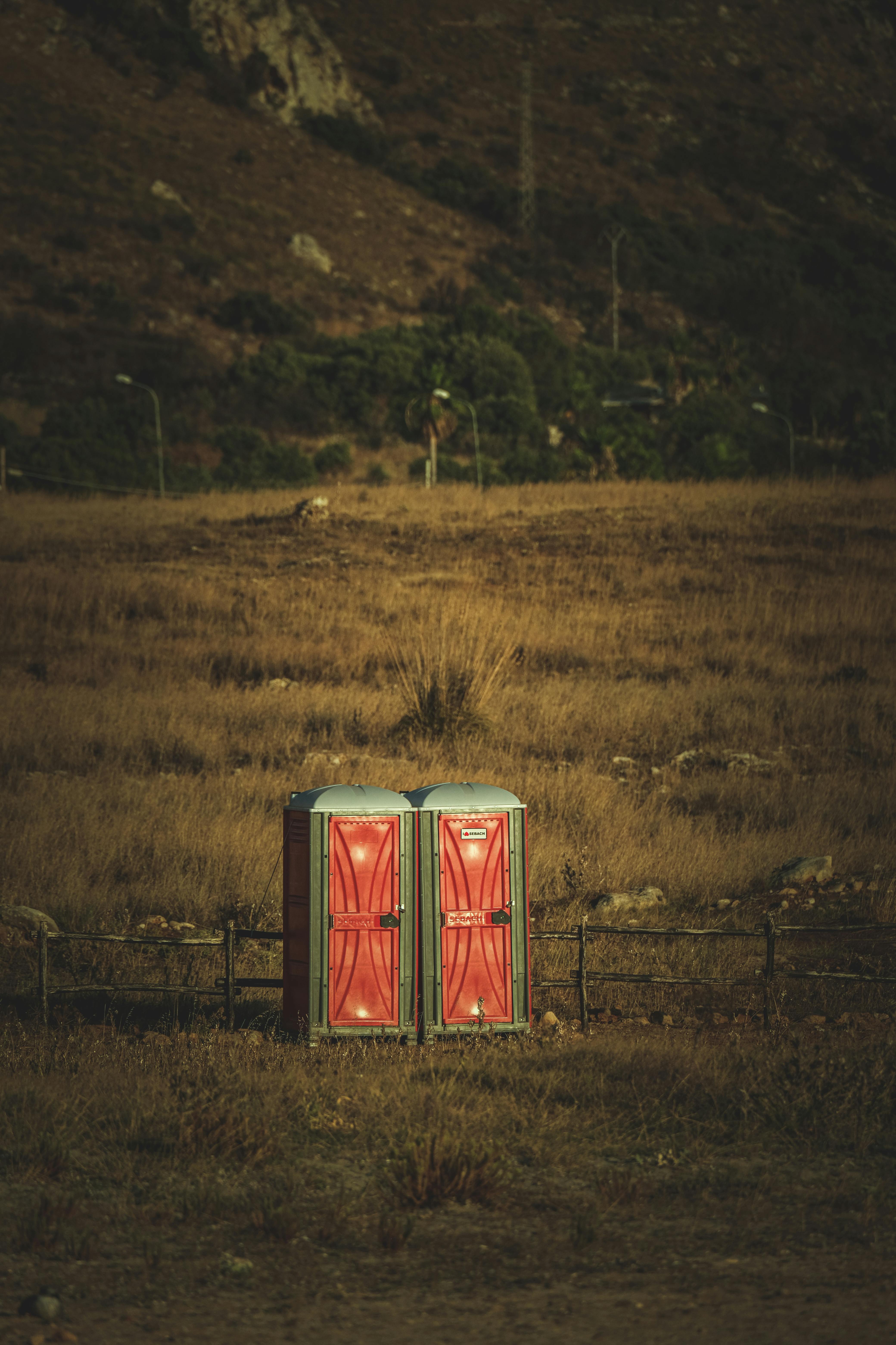Red Portable Toilets on Grassland · Free Stock Photo