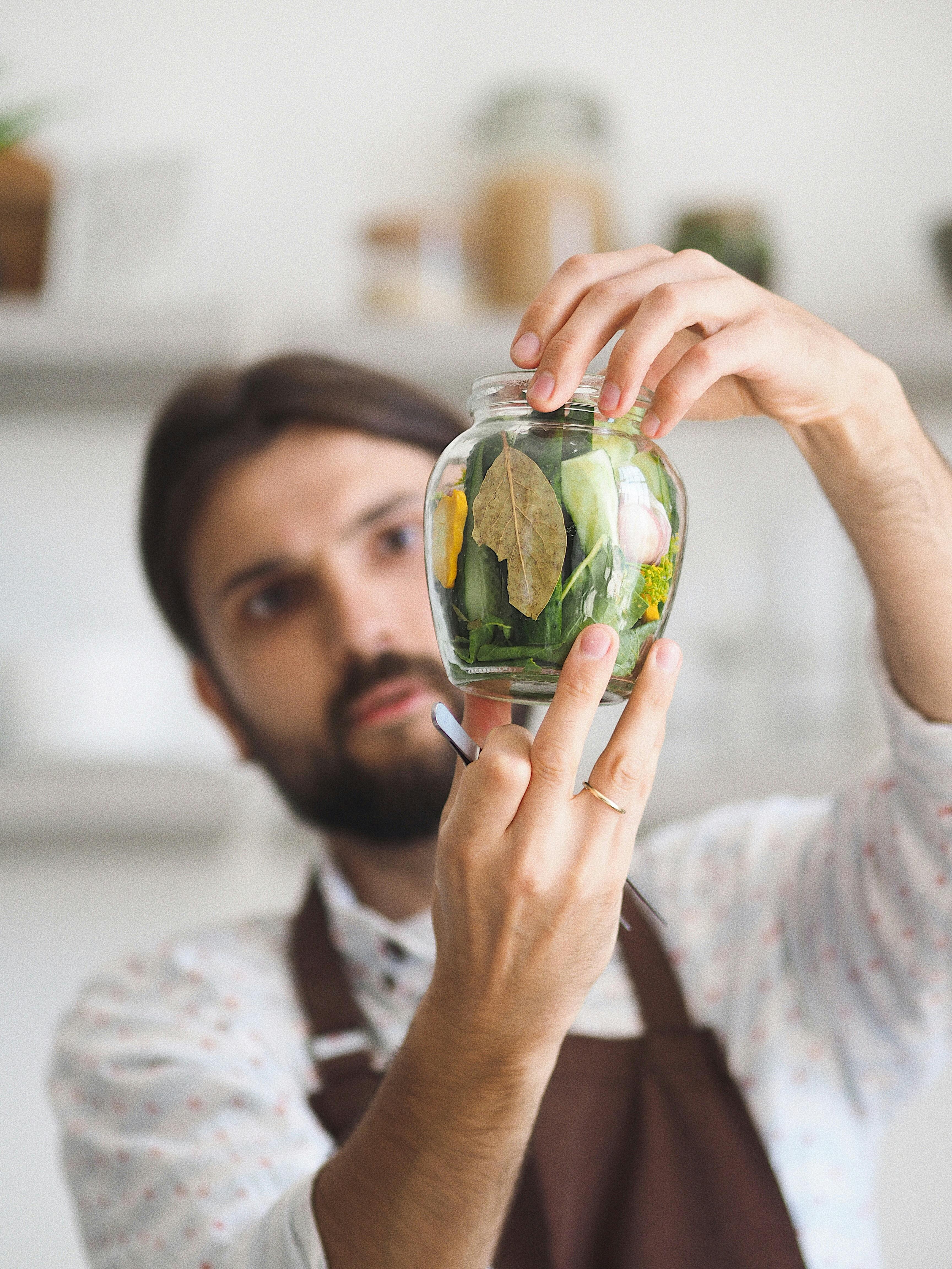 A Man Holding a Glass Jar with Assorted Herbs · Free Stock Photo