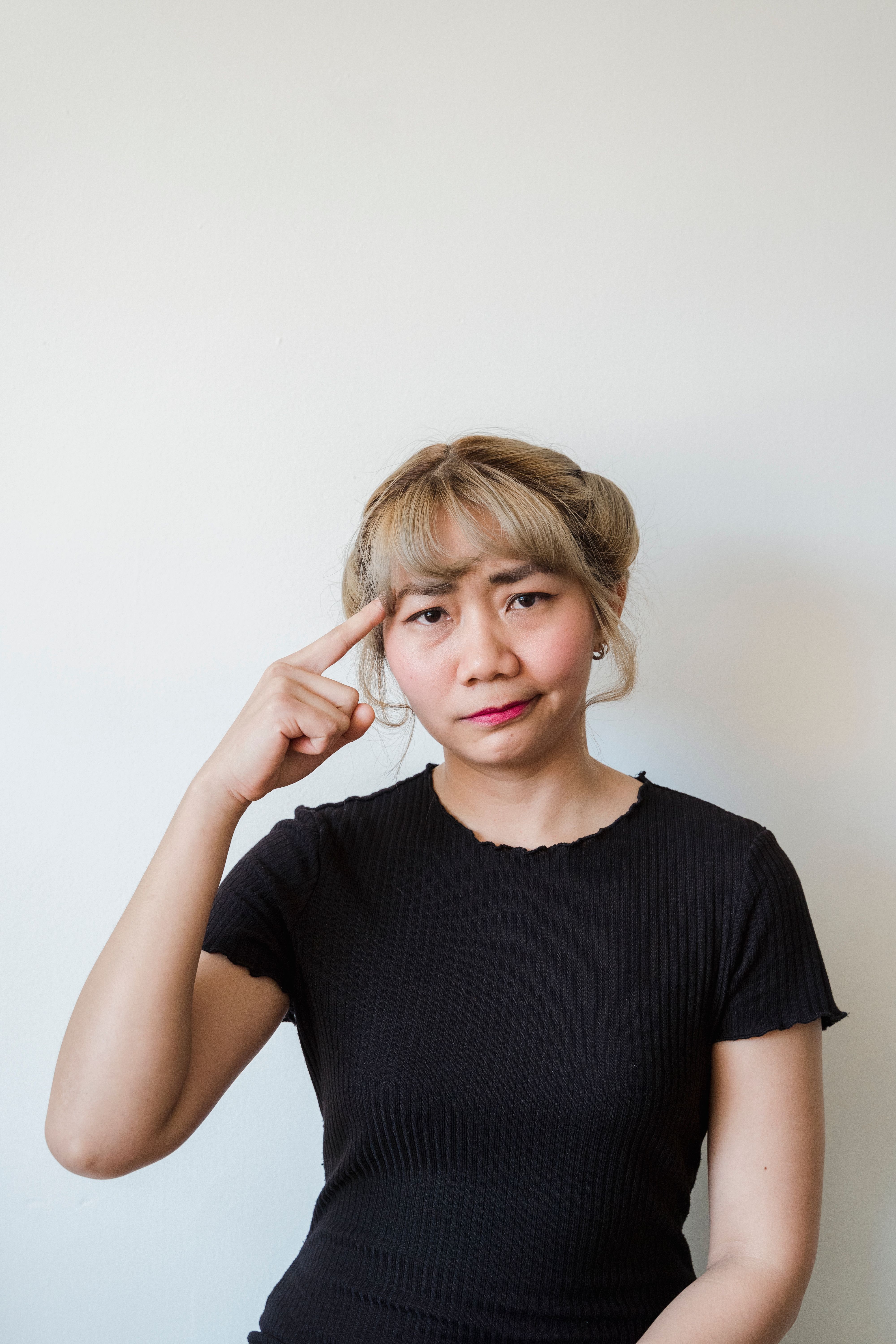 A Woman in Black Shirt Pointing on Her Head · Free Stock Photo