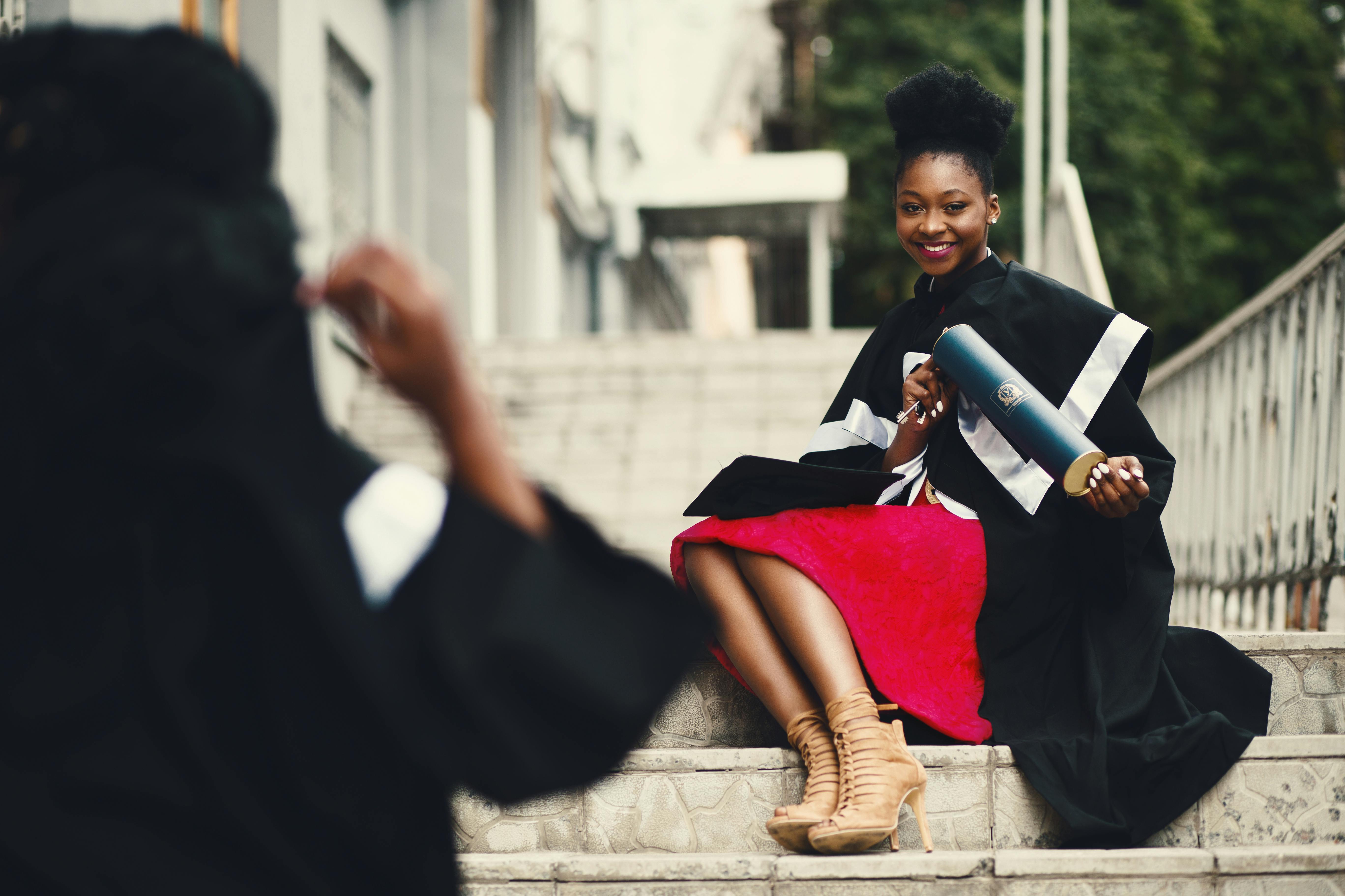 Woman Wearing Black Graduation Coat Sits on Stairs · Free Stock Photo