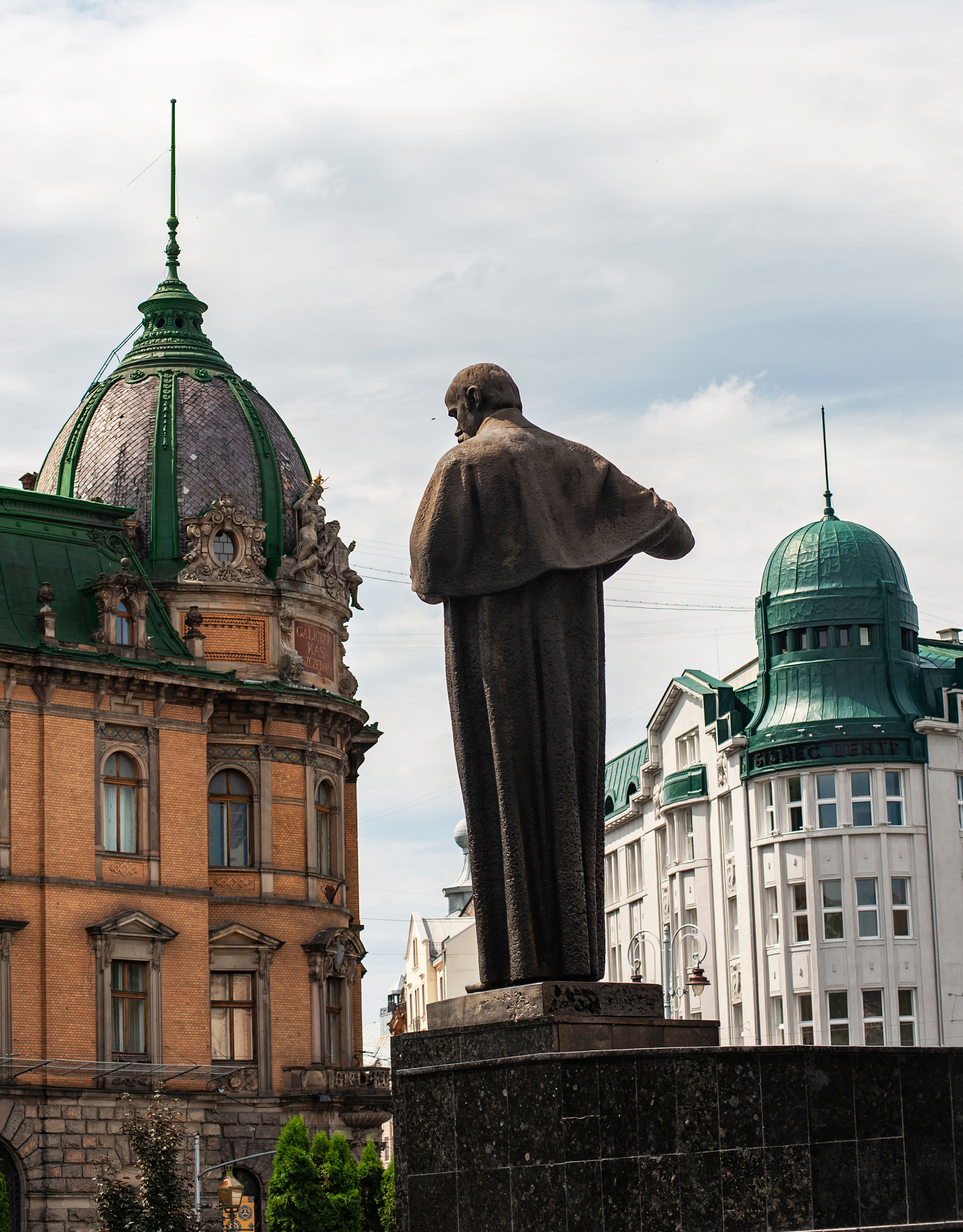 Brown Concrete Statue Near Concrete Buildings · Free Stock Photo