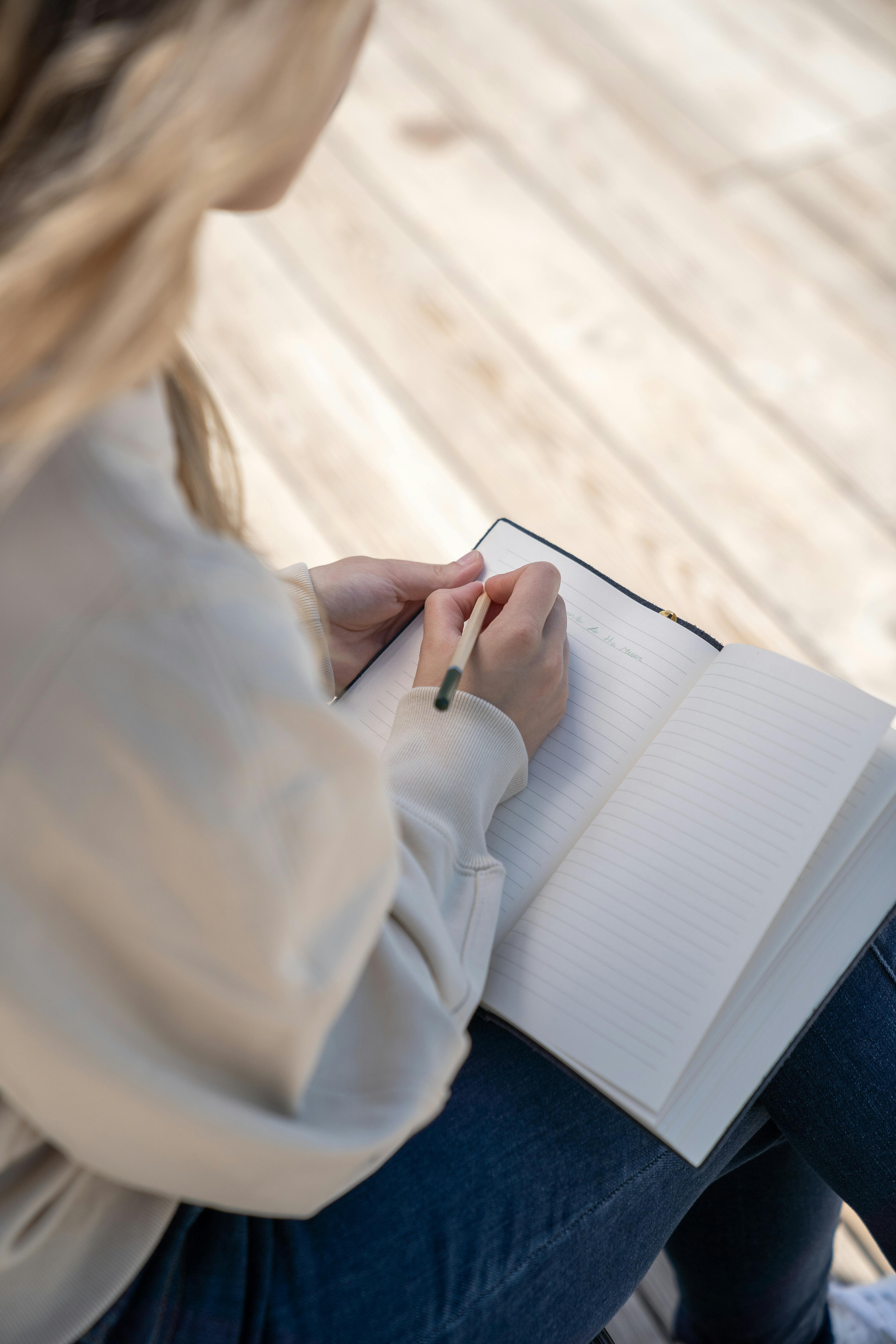 A Woman with a Brown Pen Writing on a Notebook · Free Stock Photo