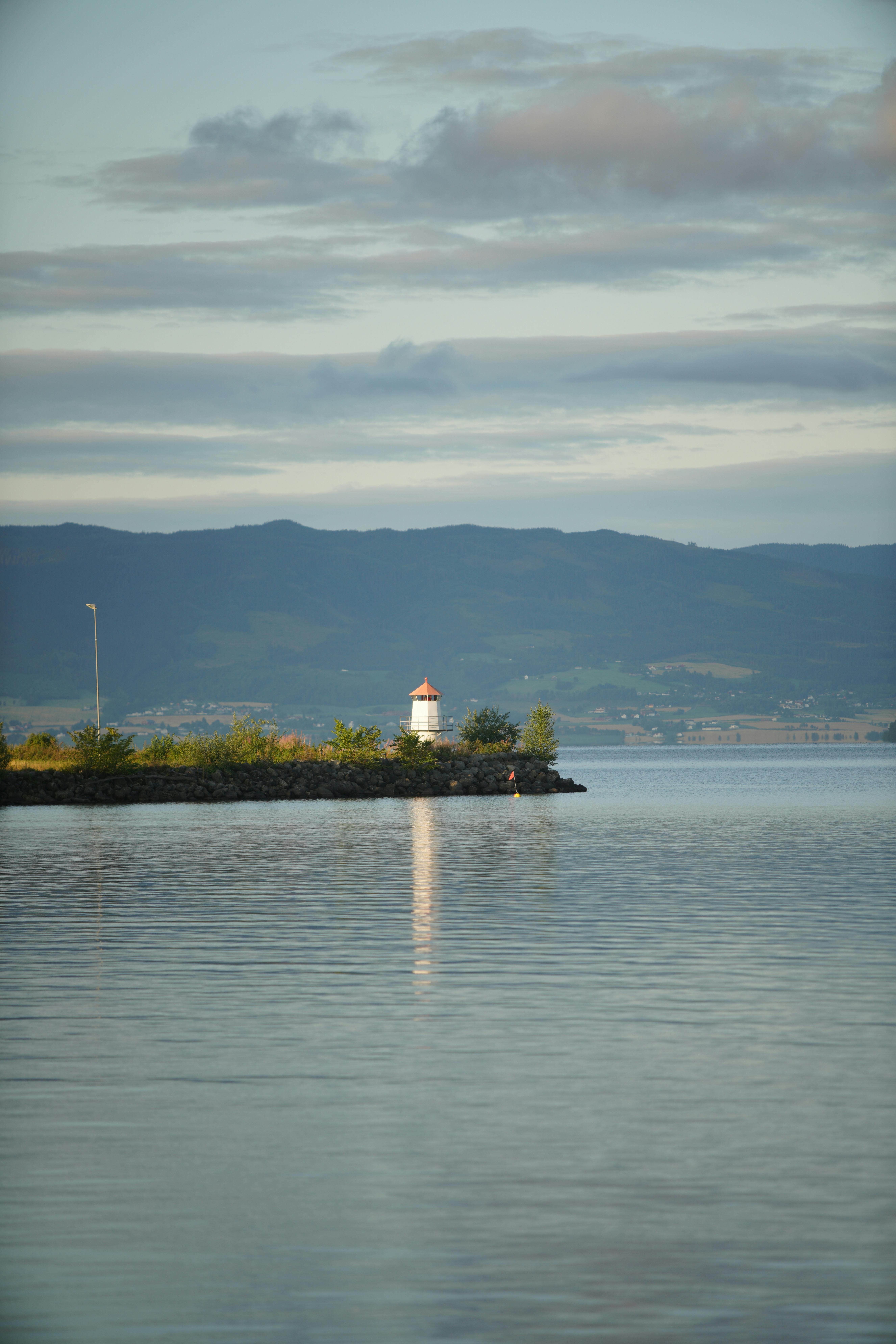 White and Brown Lighthouse Near Body of Water Under Cloudy Sky · Free ...