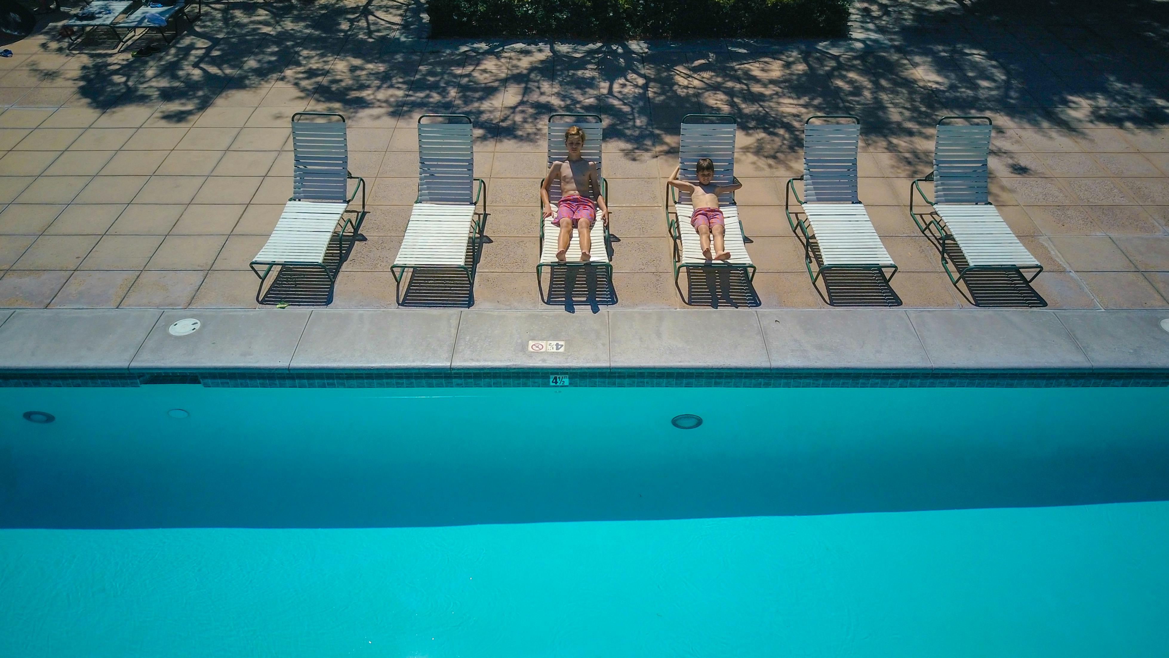 Kids Sitting on Chairs on Poolside · Free Stock Photo