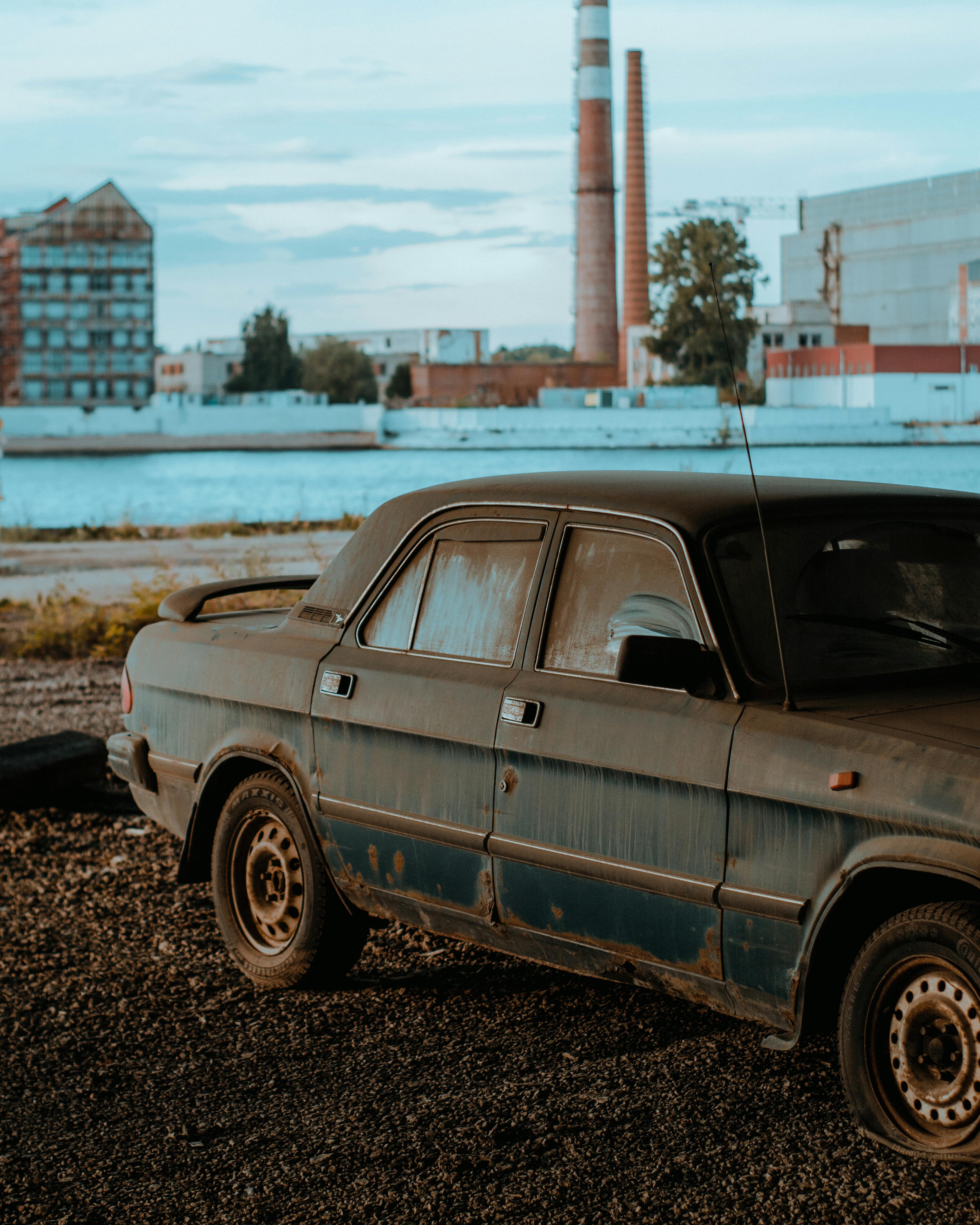 Rusty Blue Sedan Parked Near Towers · Free Stock Photo