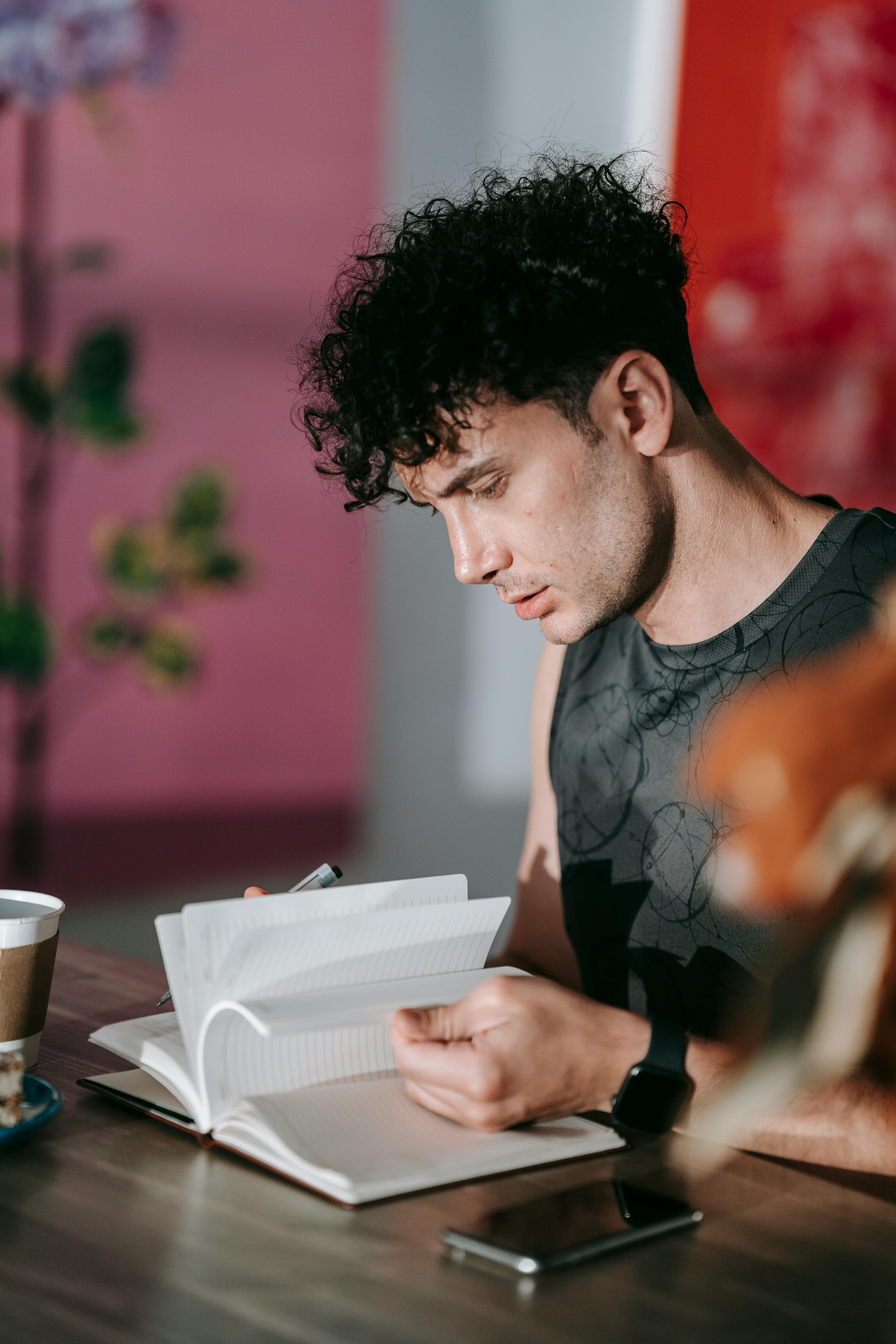 A Man in Black and Gray Crew Neck Shirt Writing on a Notebook · Free ...