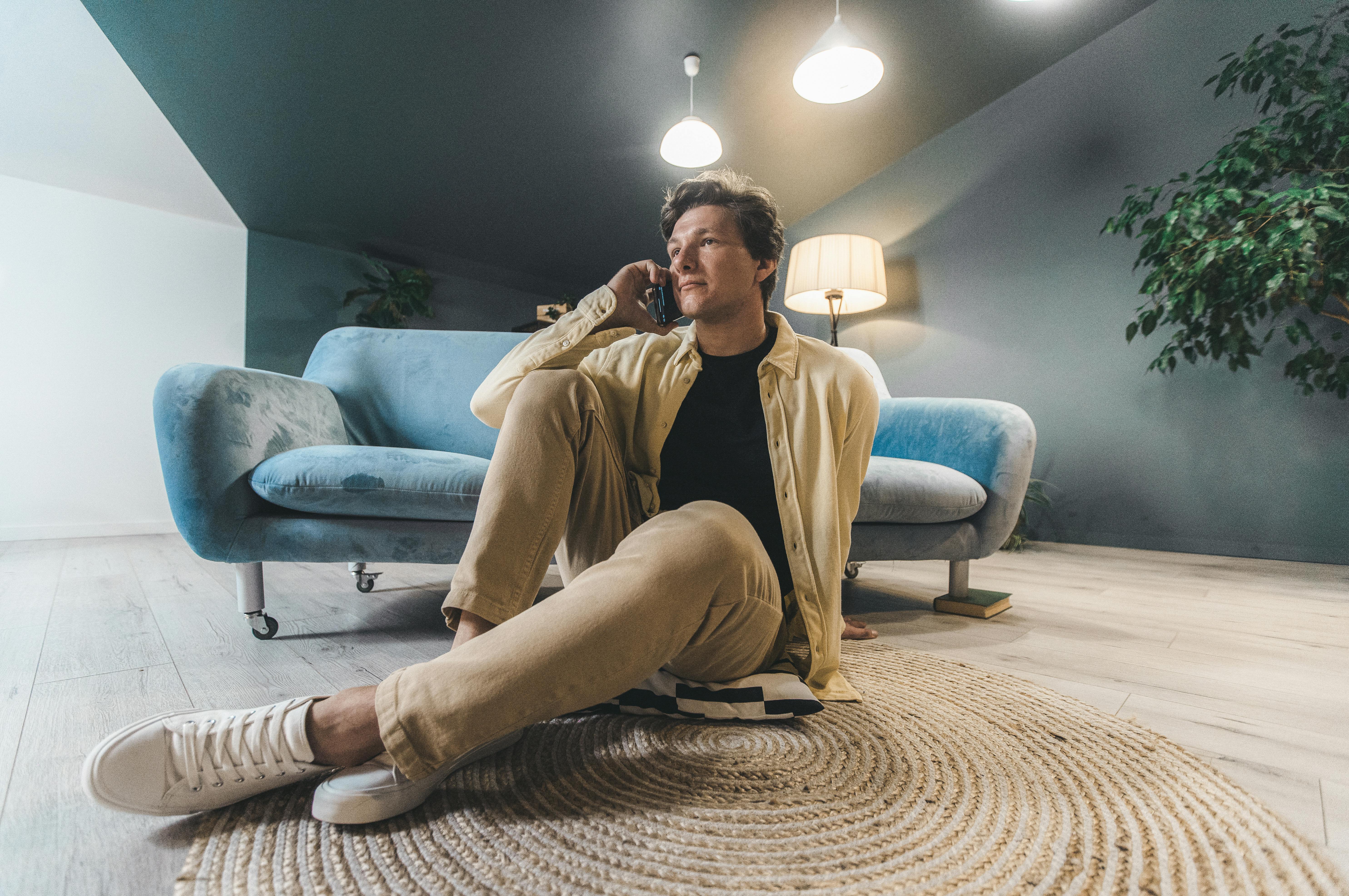 A Man Sitting on the Rug in a Wooden Floor · Free Stock Photo
