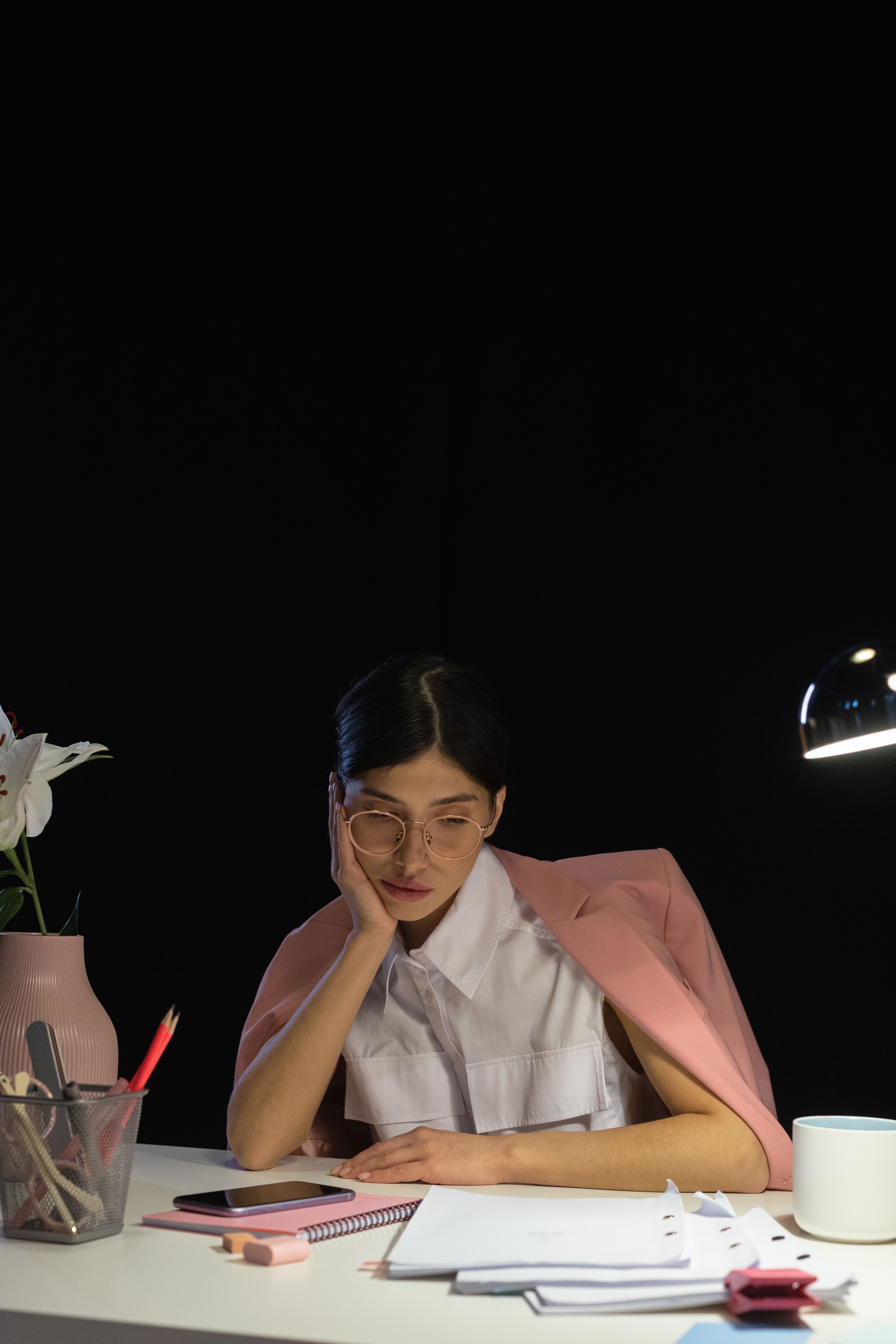 Woman Crouching on Desk Among Flying Papers in Office · Free Stock Photo