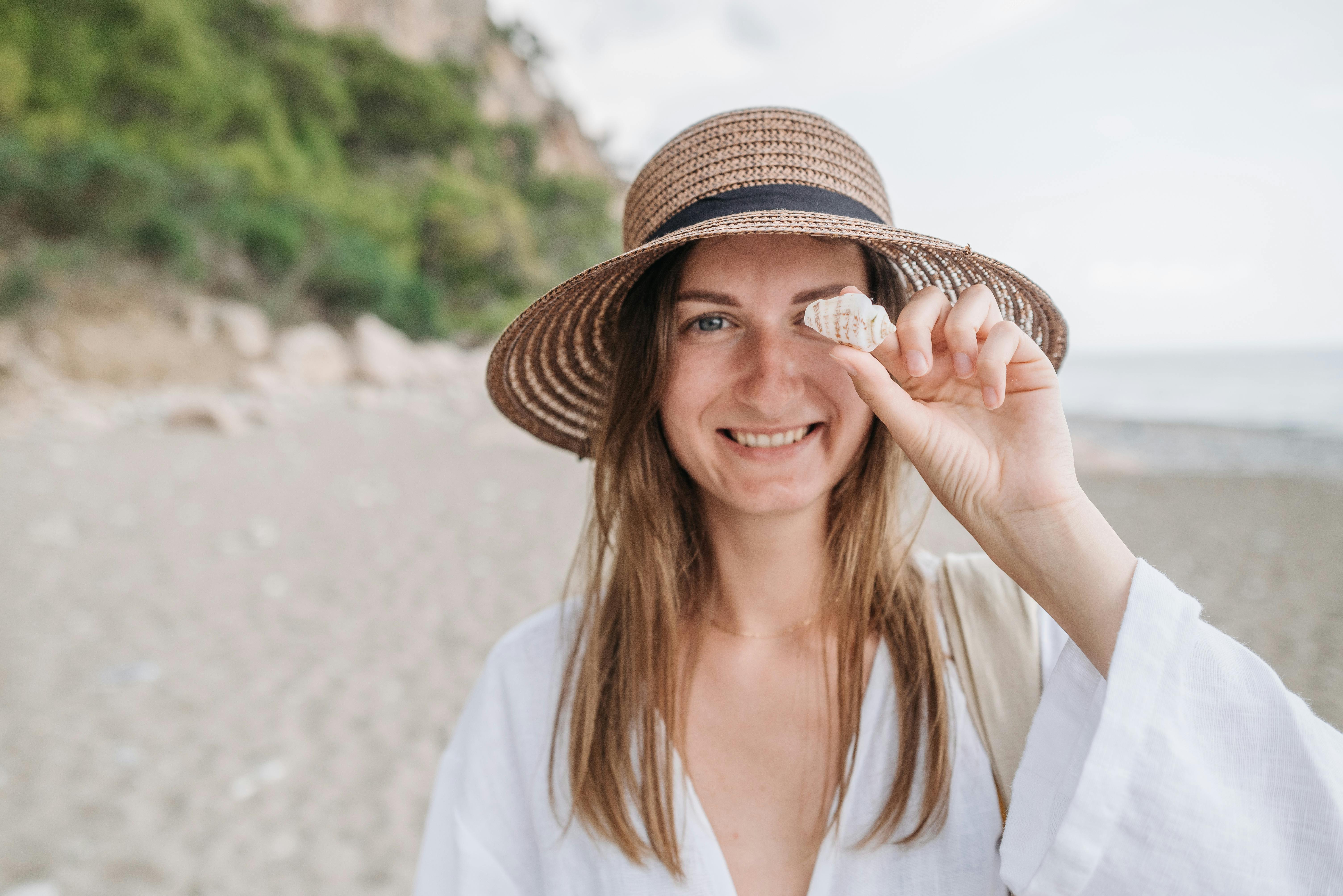 Woman Wearing Sun Hat Showing a Seashell · Free Stock Photo