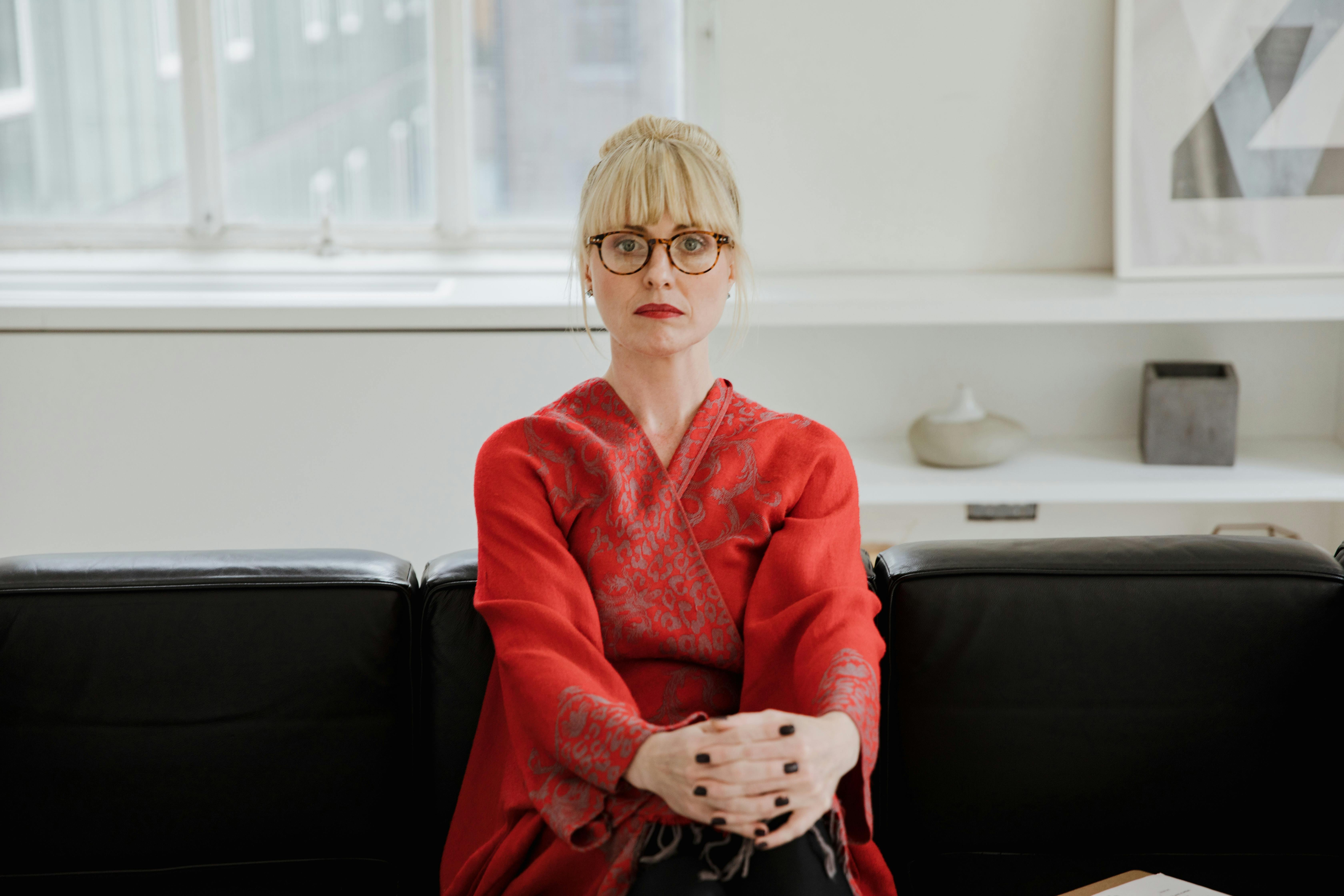 A Woman in Red Robe Sitting on Leather Couch · Free Stock Photo