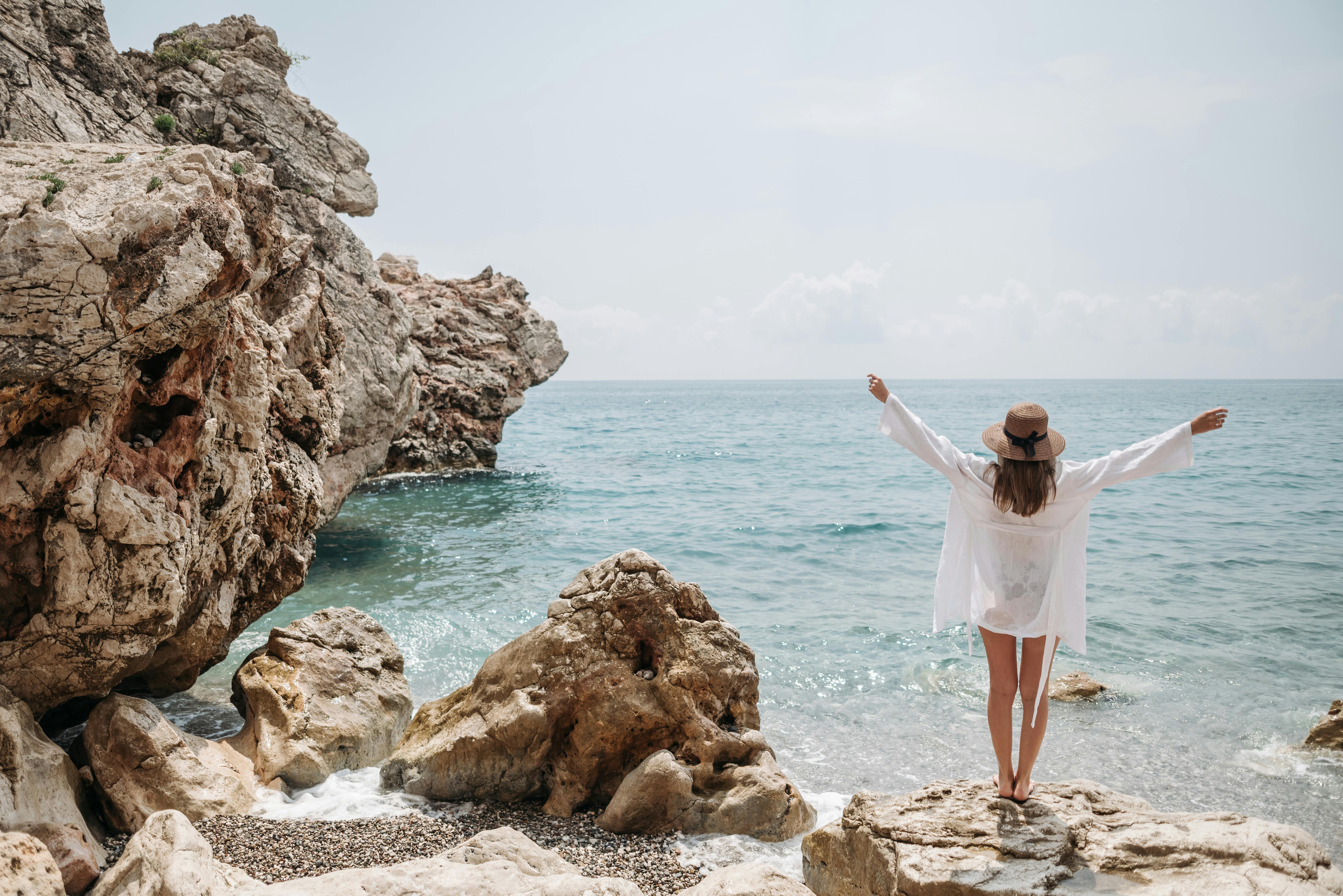 A Woman Standing on a Rock at the Beach · Free Stock Photo