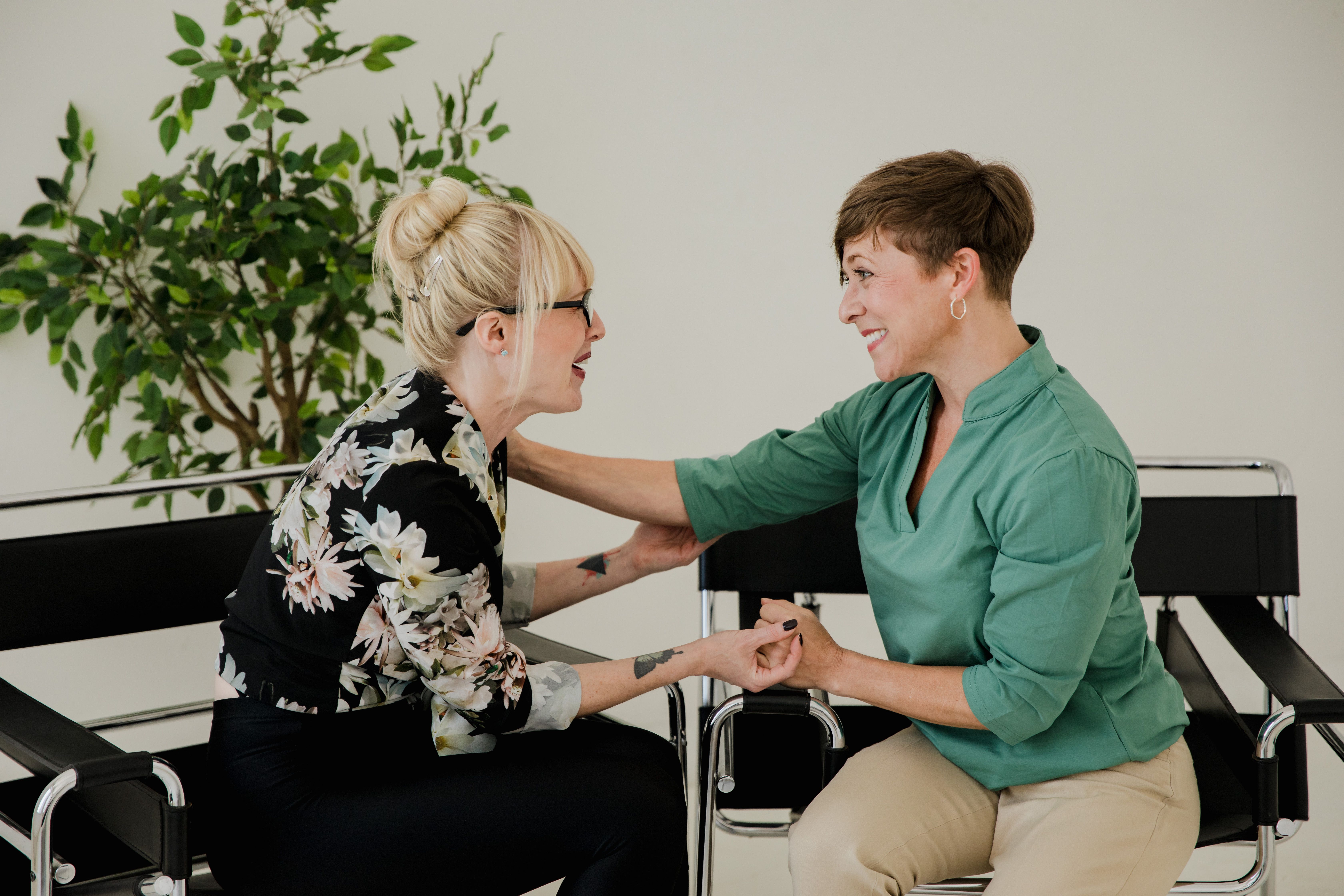 Women Sitting on Chairs, Holding Hands and Smiling · Free Stock Photo