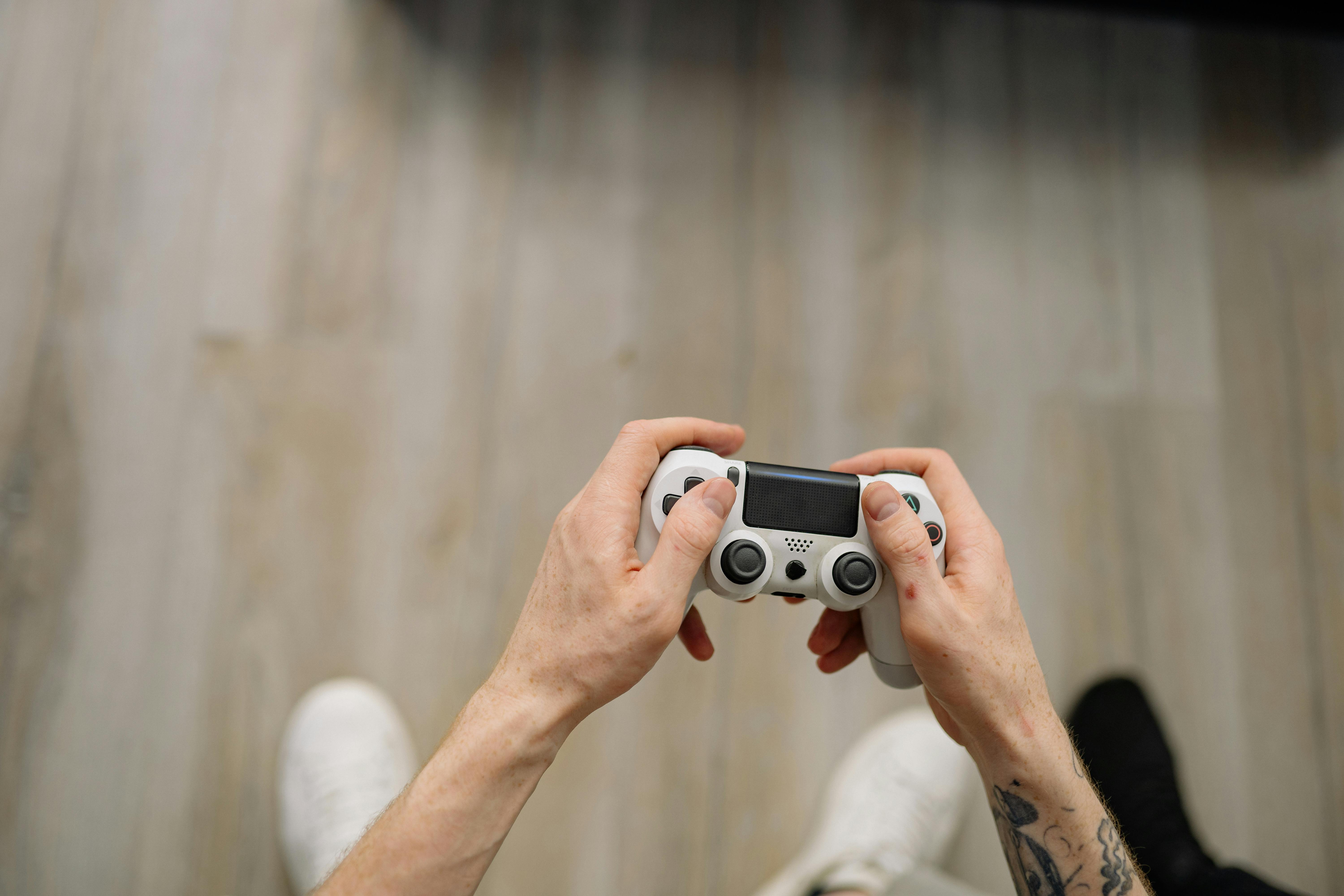 A Person Sitting on Gray Couch Holding a Game Controller · Free Stock Photo