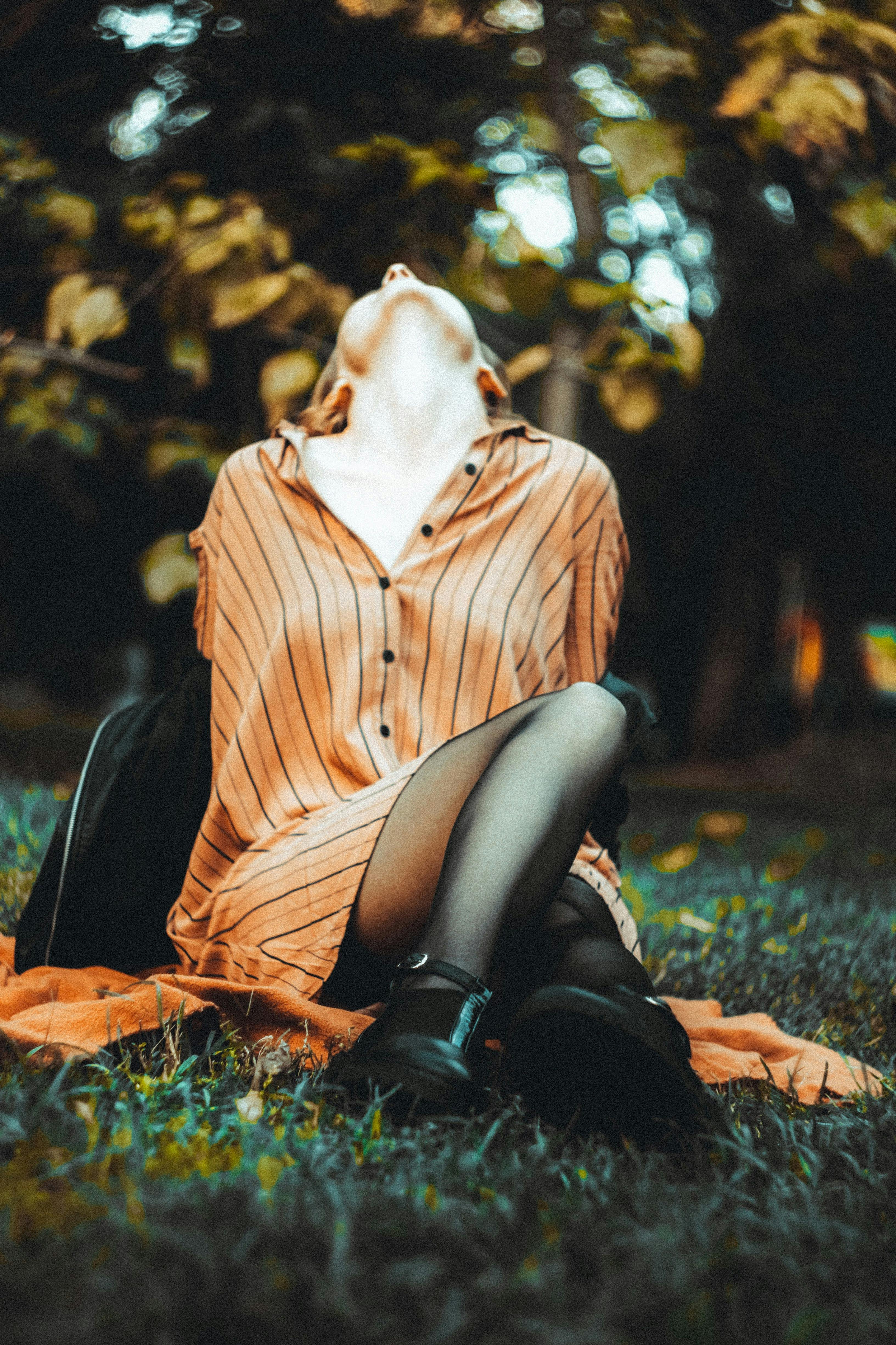 A Woman in a Striped Dress Sitting on Grass · Free Stock Photo
