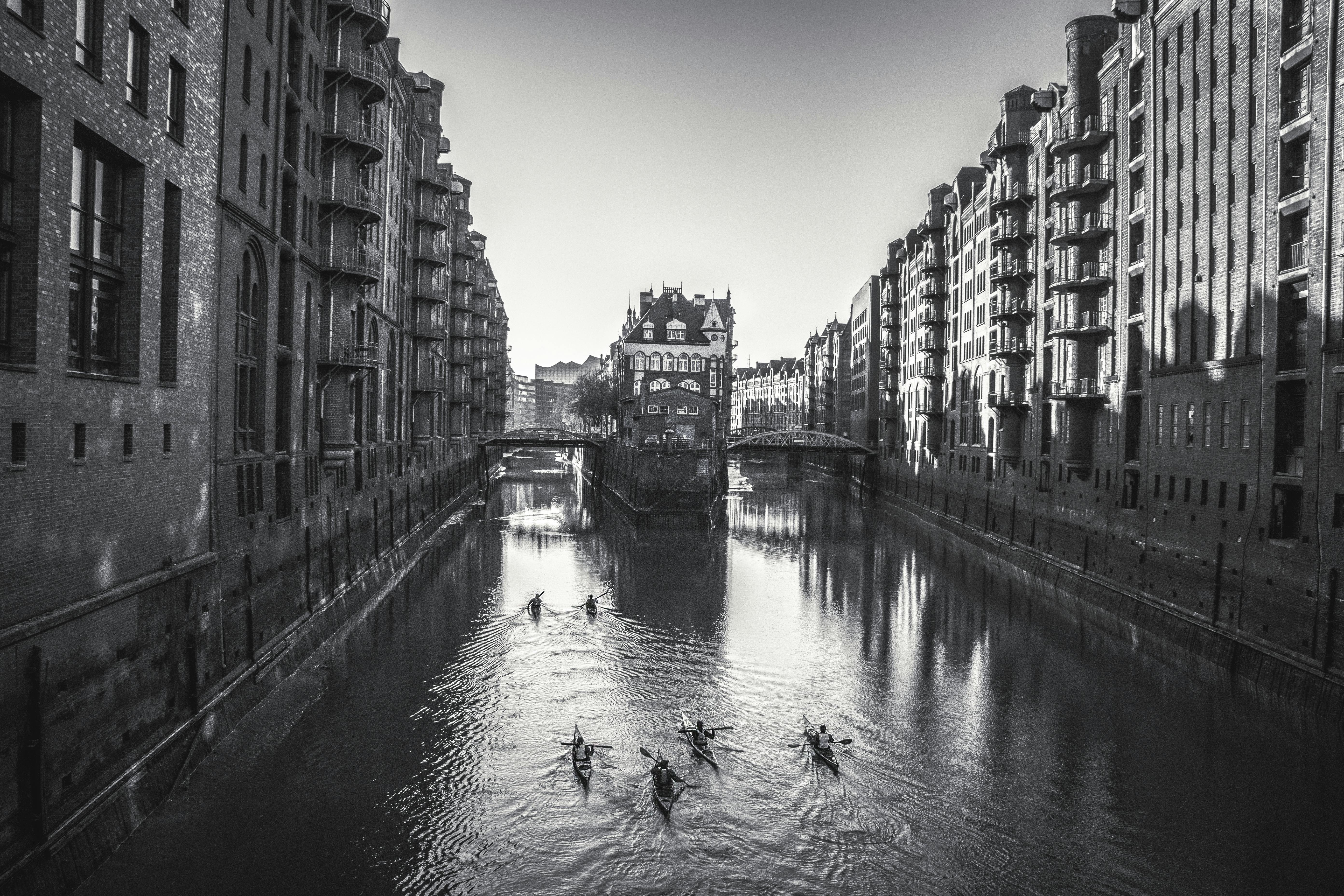 People Kayaking on a River Between Buildings · Free Stock Photo