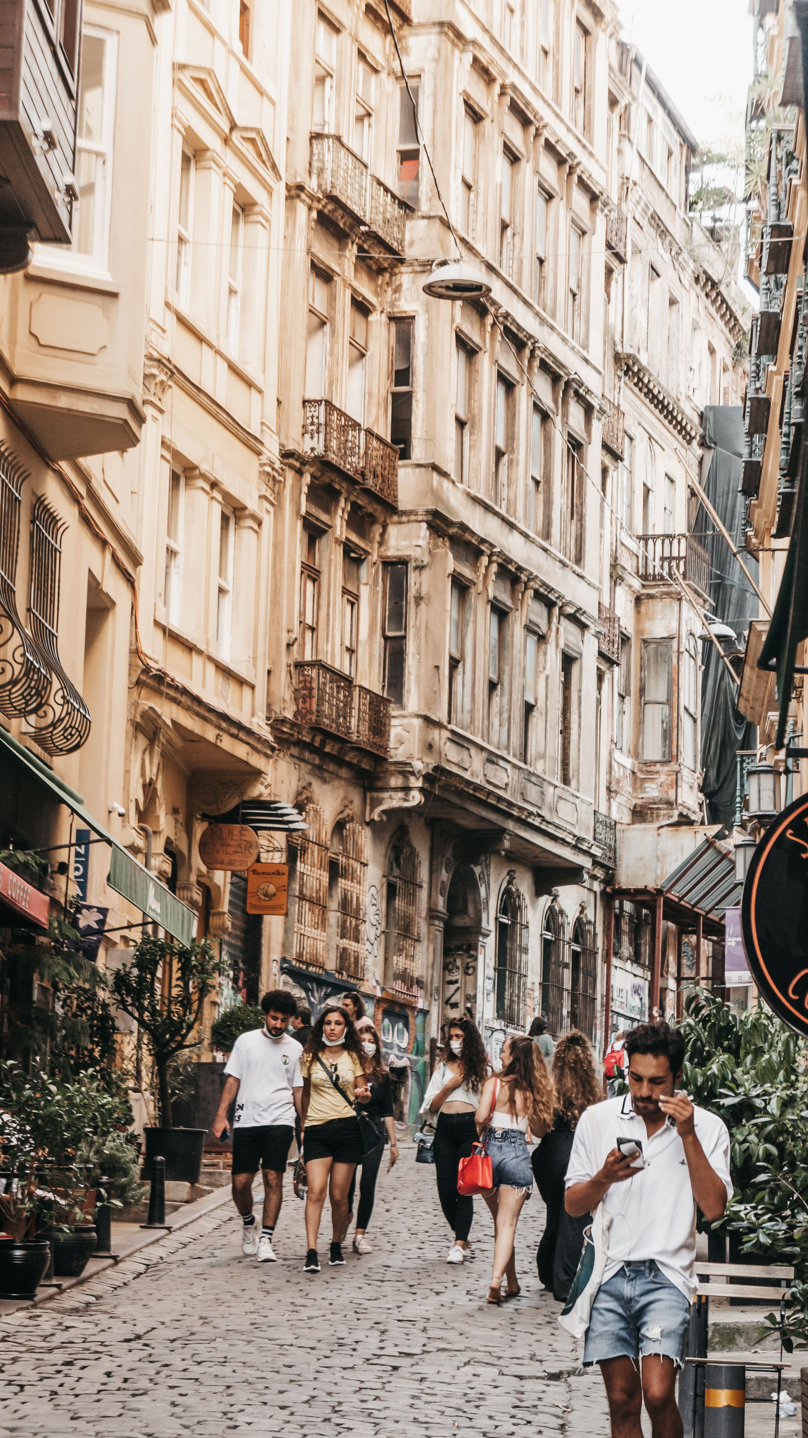 People Walking between the Tall Concrete Buildings · Free Stock Photo