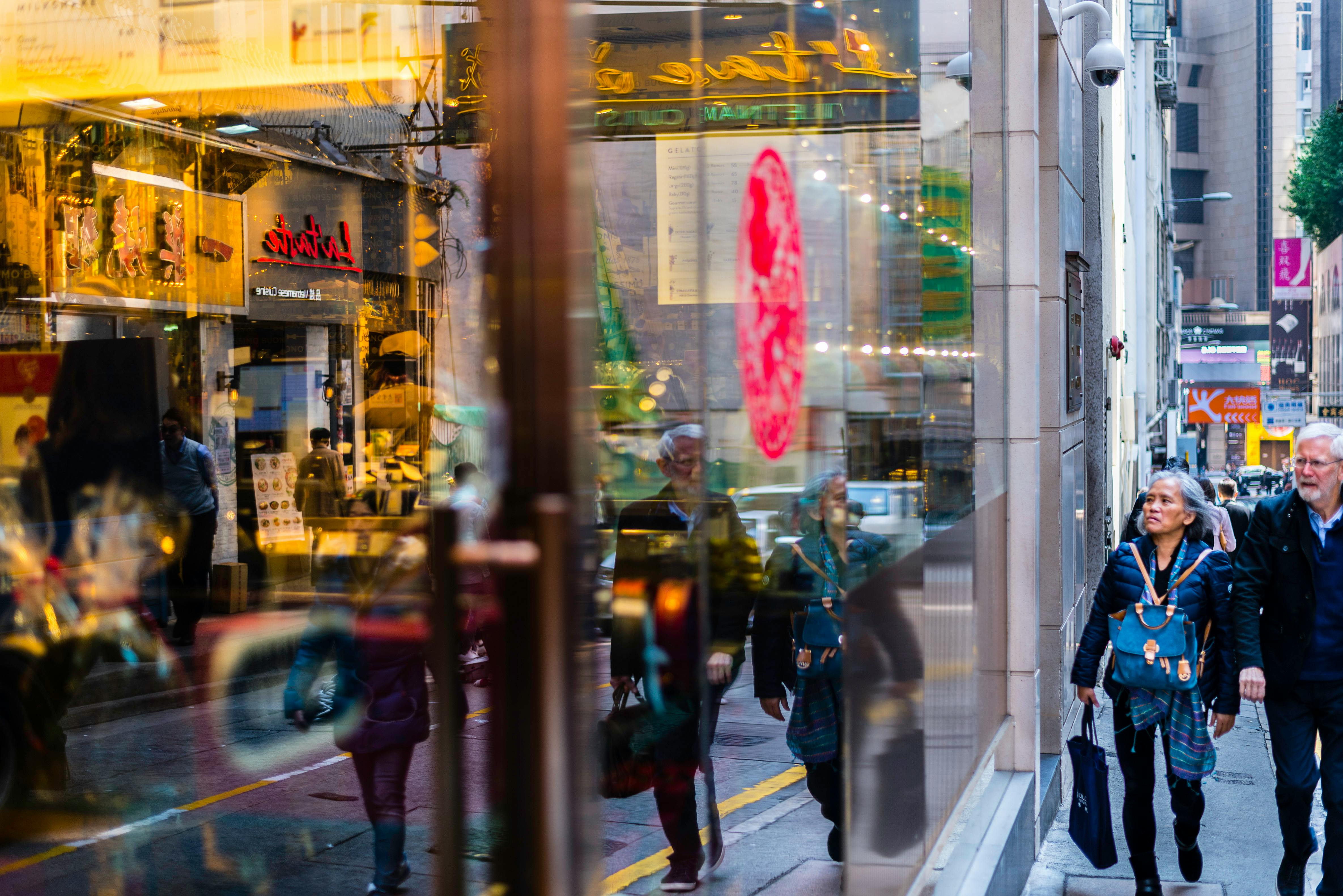Man and Woman Passing Through Building With Glass Facade · Free Stock Photo
