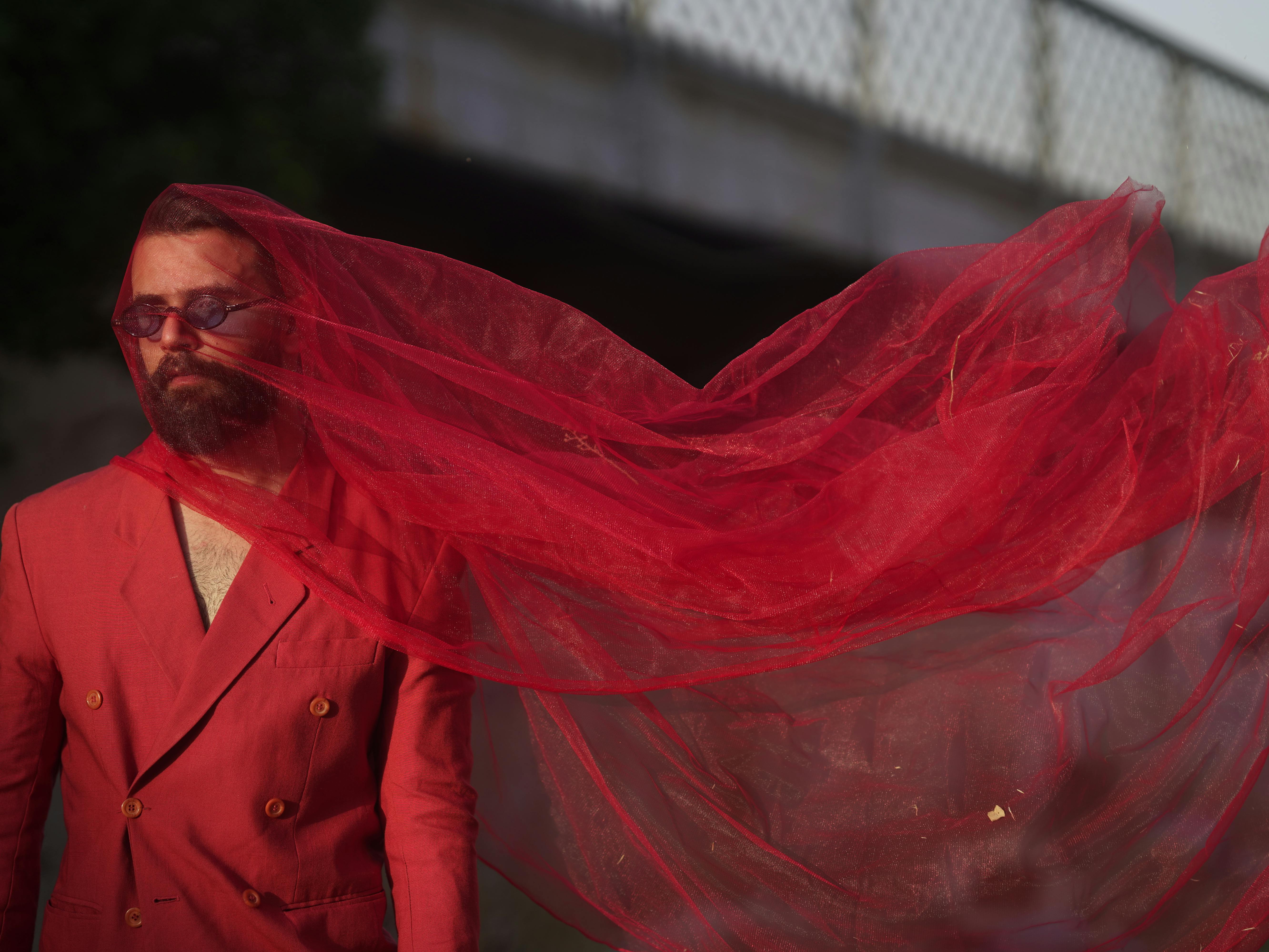 Man on a Fashion Shoot Wearing a Red Suit and Sheer Red Fabric Over His ...