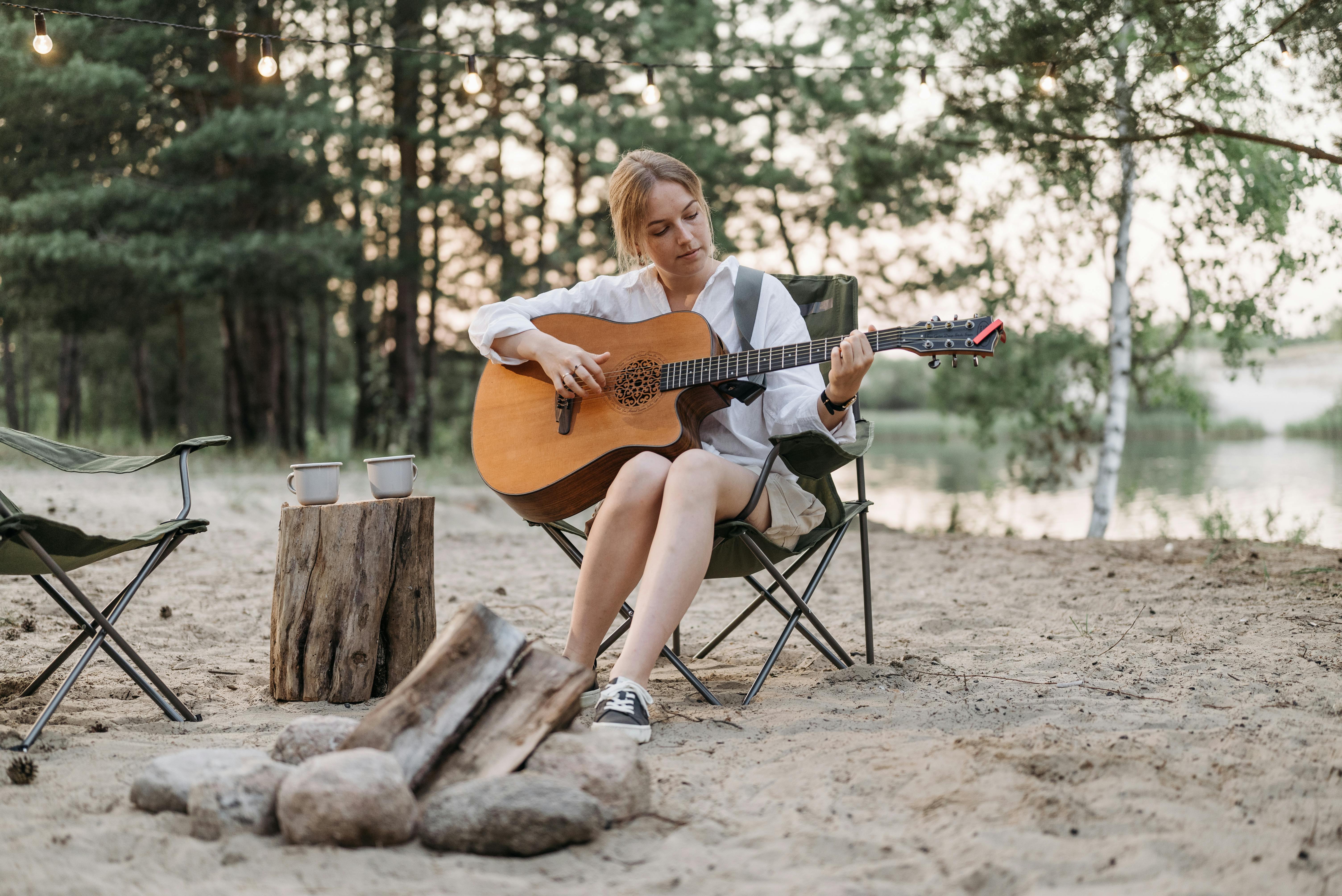 Woman Sitting on a Chair Playing Guitar · Free Stock Photo