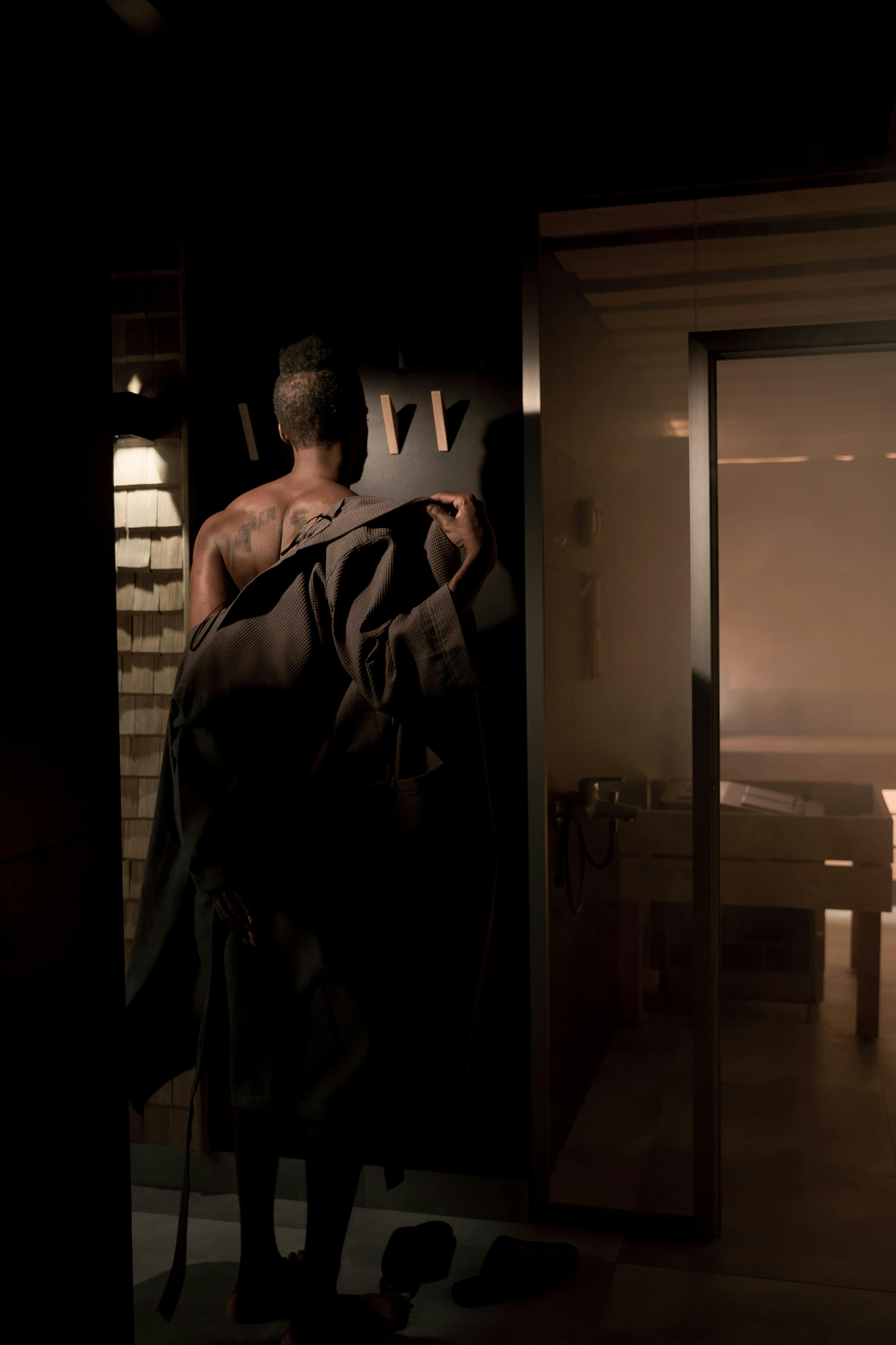 A Man Taking Off his Coat Near a Glass Door · Free Stock Photo