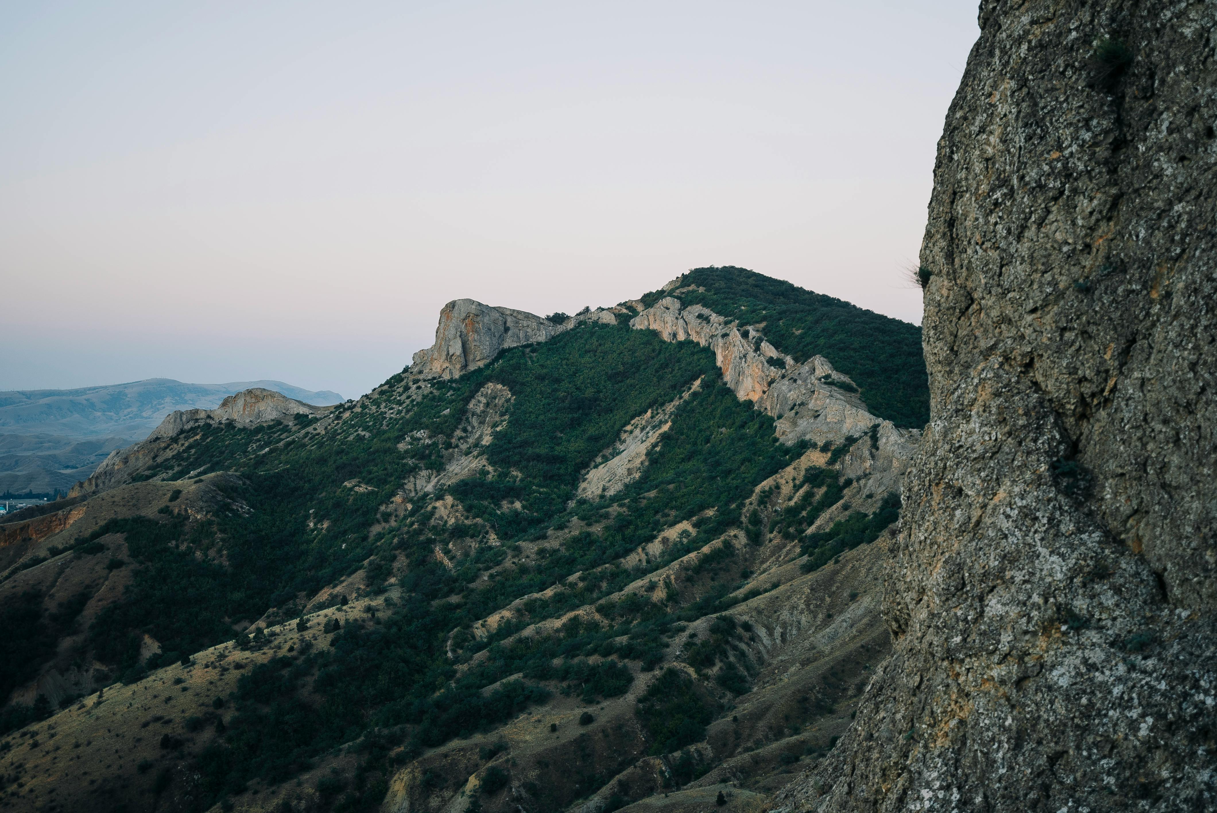 Man Sitting on Rocks over Precipice in Mountains · Free Stock Photo