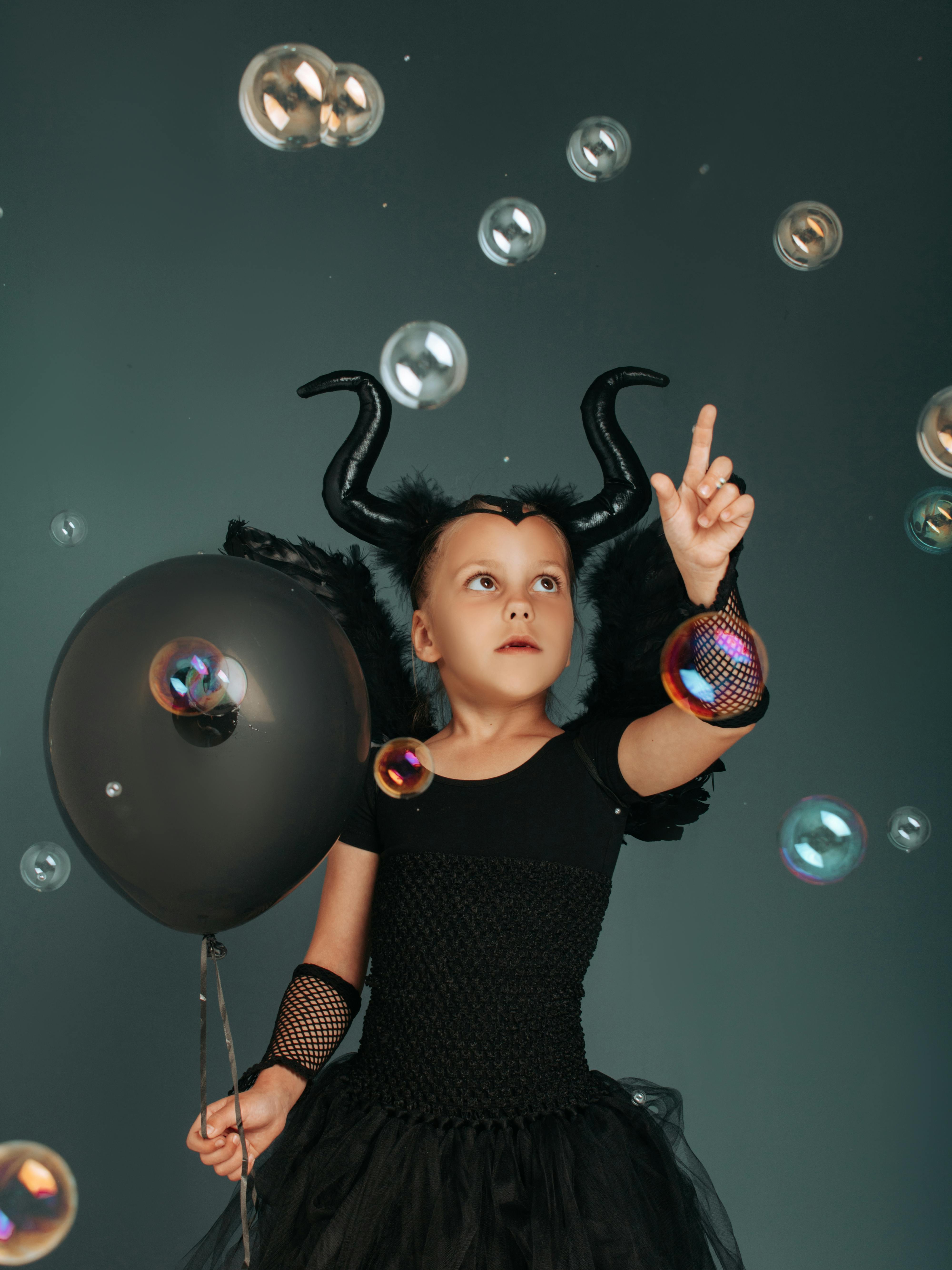 A Girl in Black Maleficent Costume Holding a Balloon · Free Stock Photo
