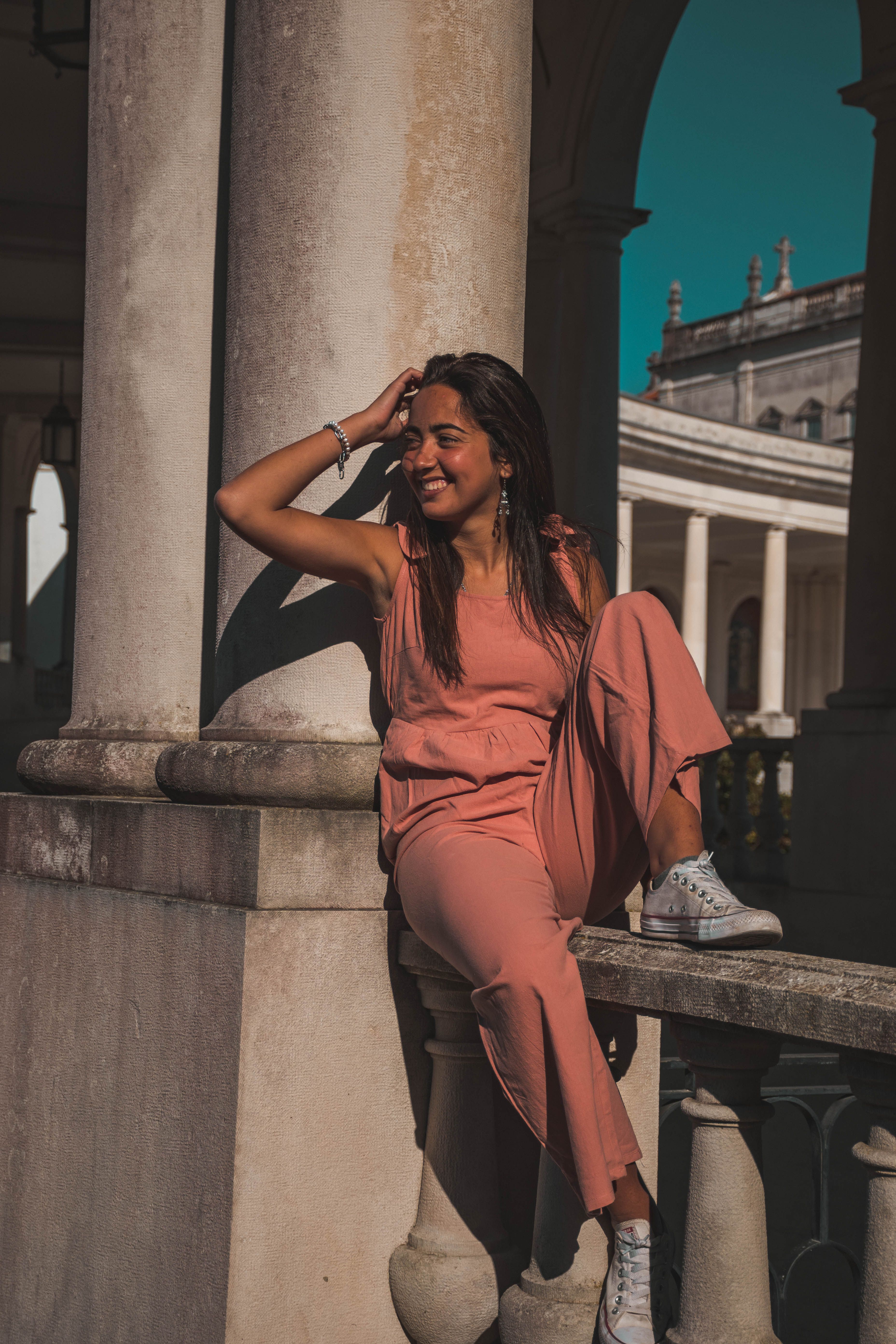 Smiling Woman Sitting on Column · Free Stock Photo