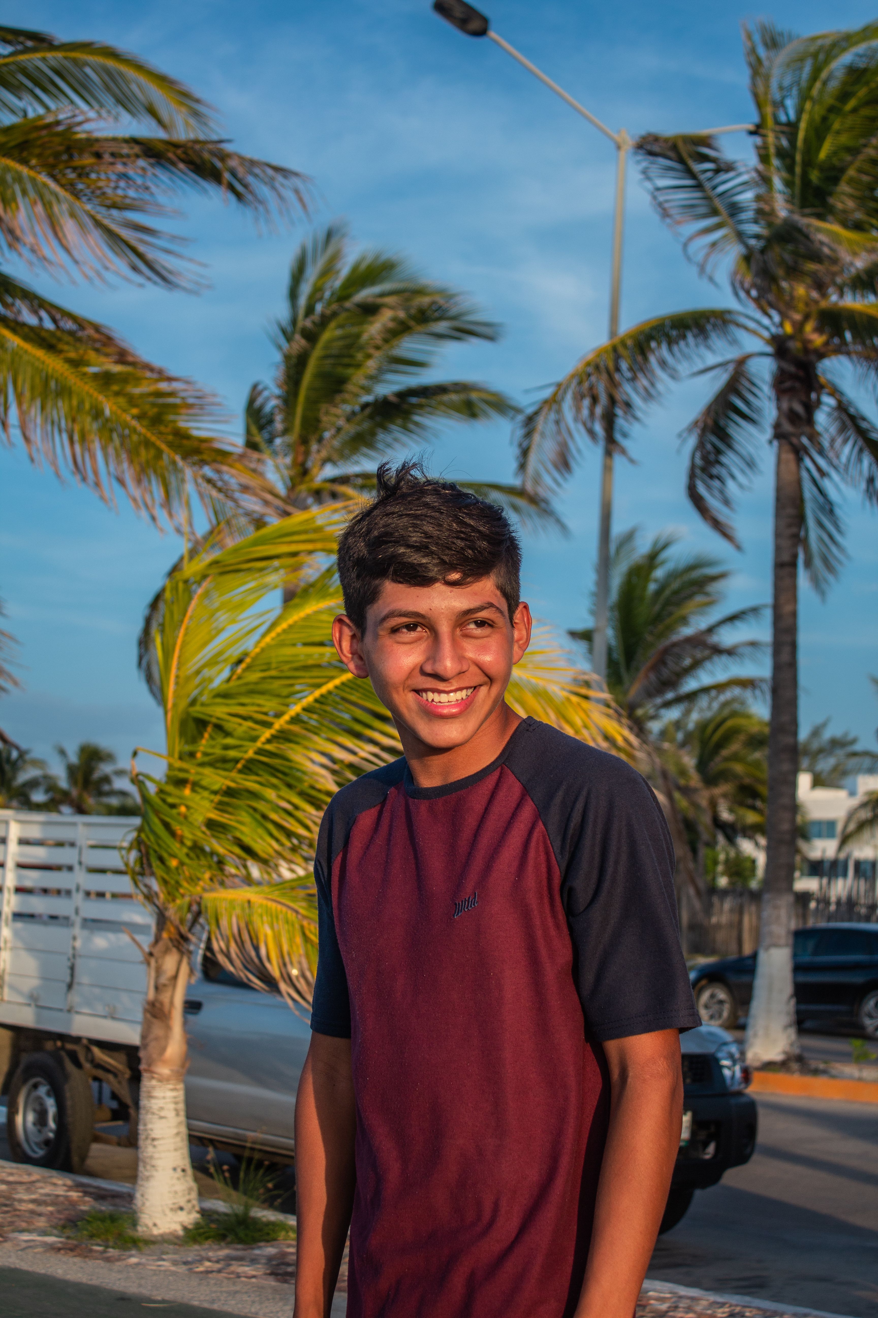 Smiling Boy With Palm Trees in the Background · Free Stock Photo