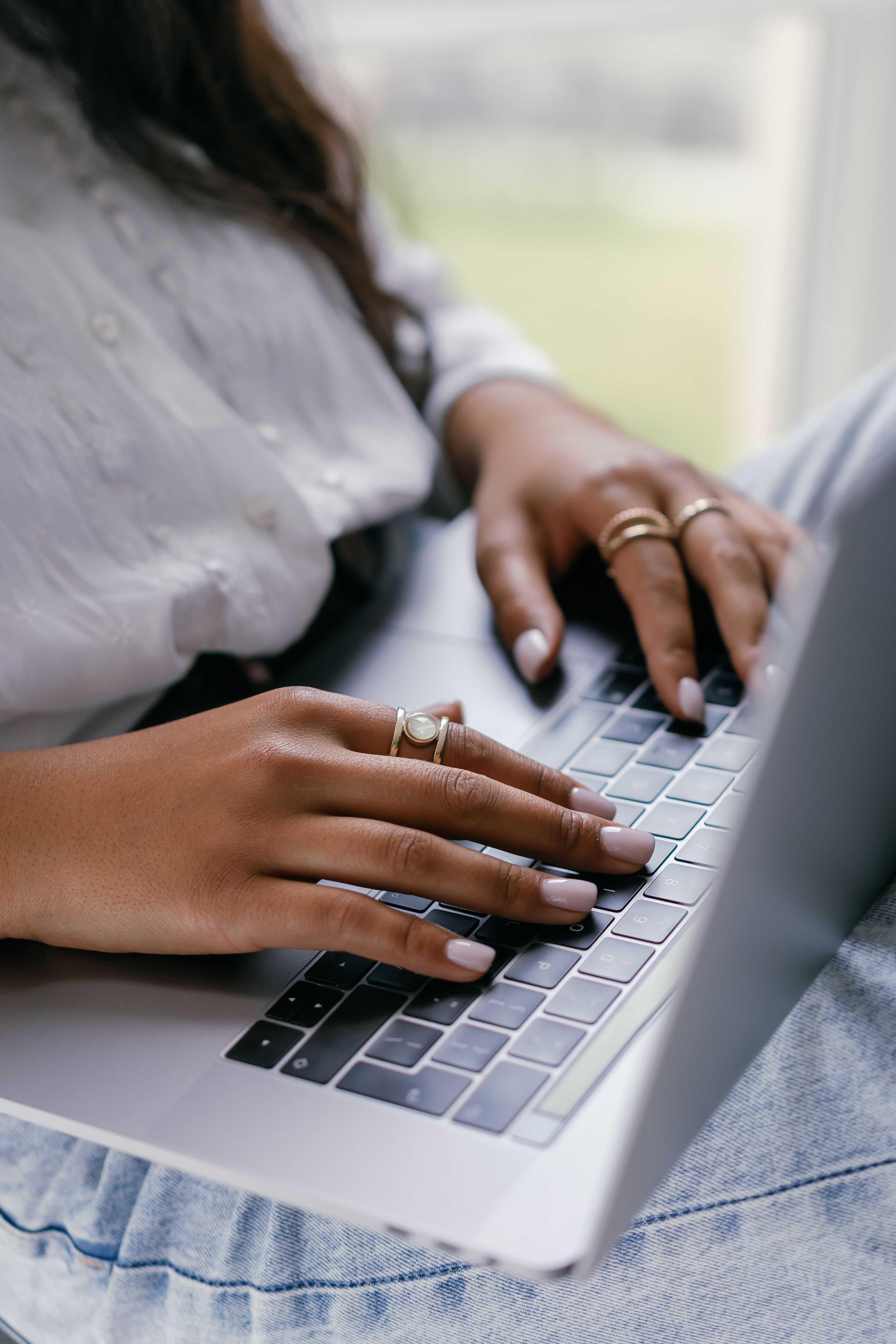 A Person Sitting Beside the Glass Window using a Laptop · Free Stock Photo