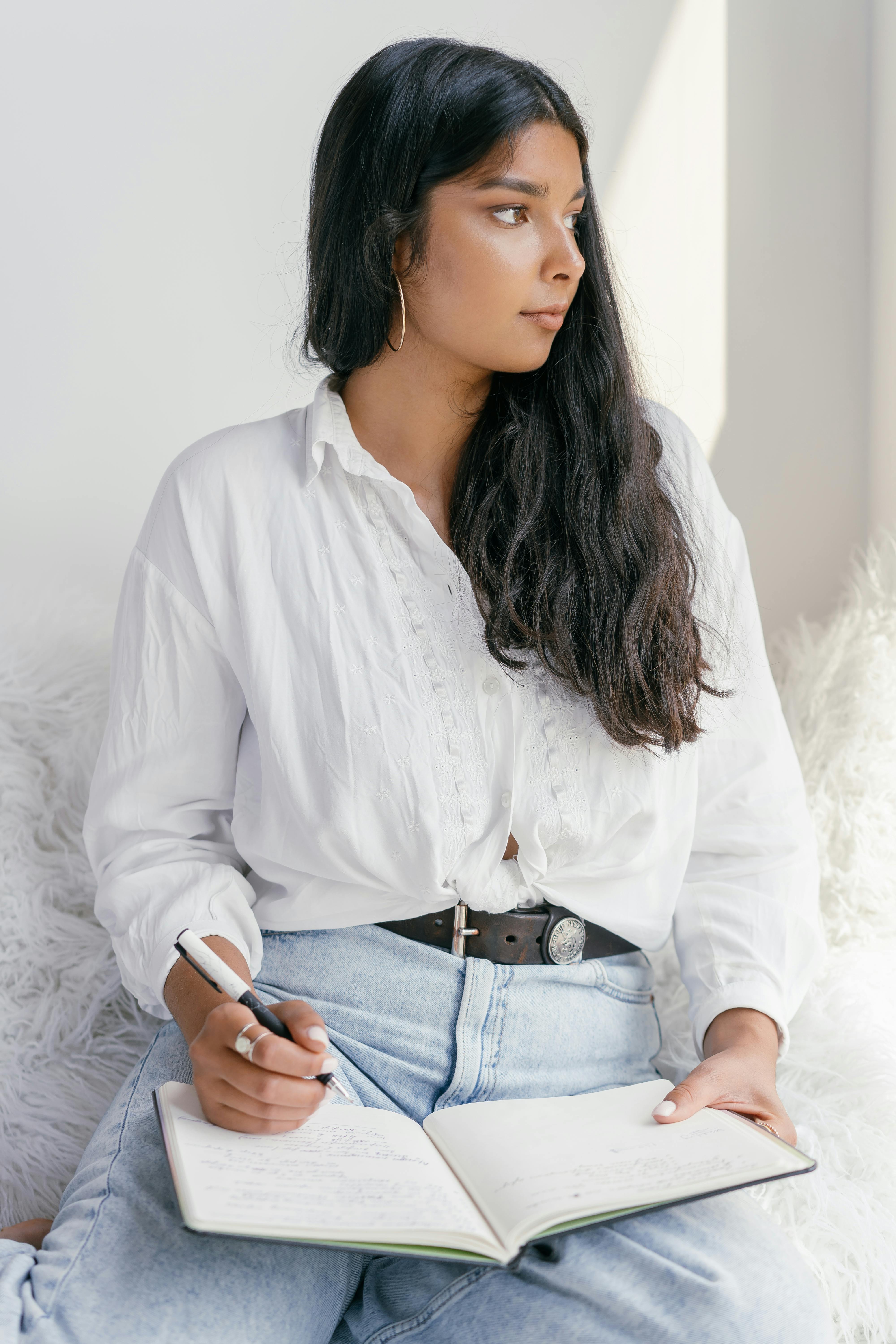 A Woman Looking To Her Left While Holding Her Notebook · Free Stock Photo