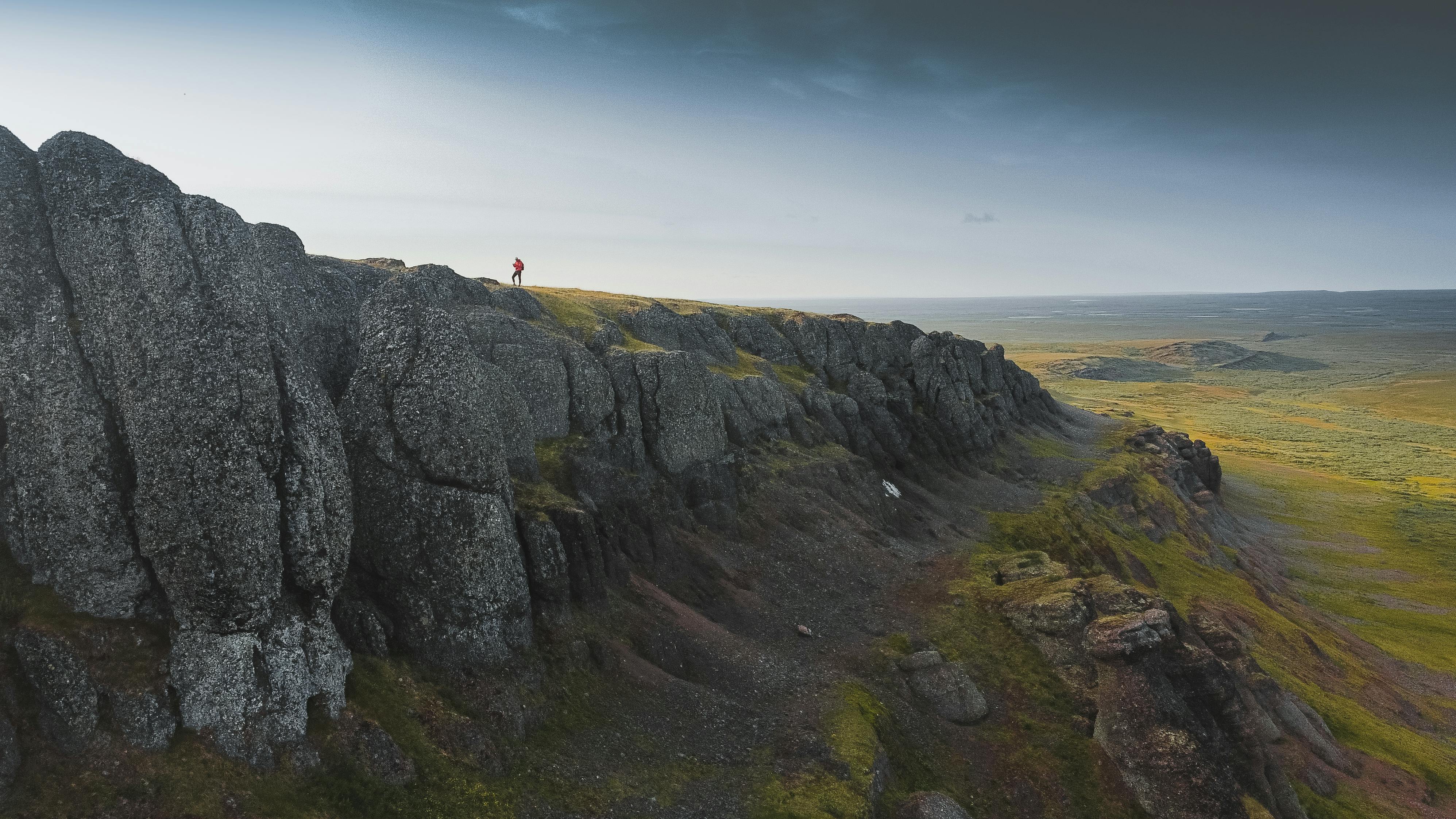 Person Hiking on Cliff in Mountain Landscape · Free Stock Photo