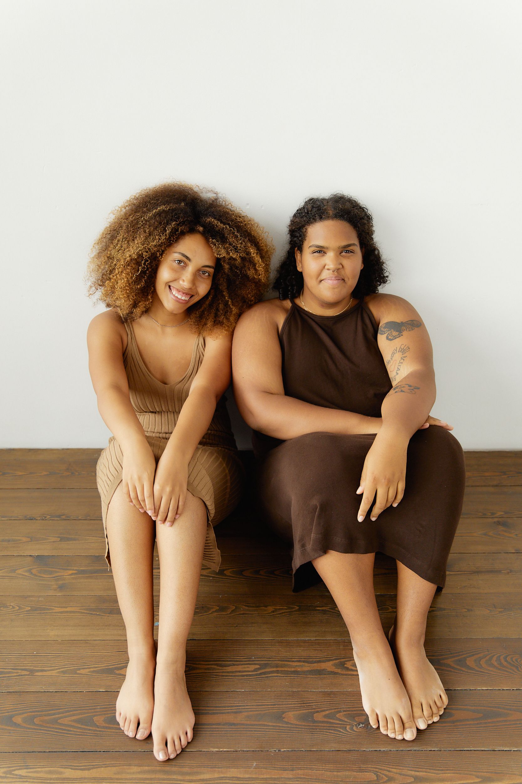 Two Women Sitting Together on the Wooden Floor · Free Stock Photo