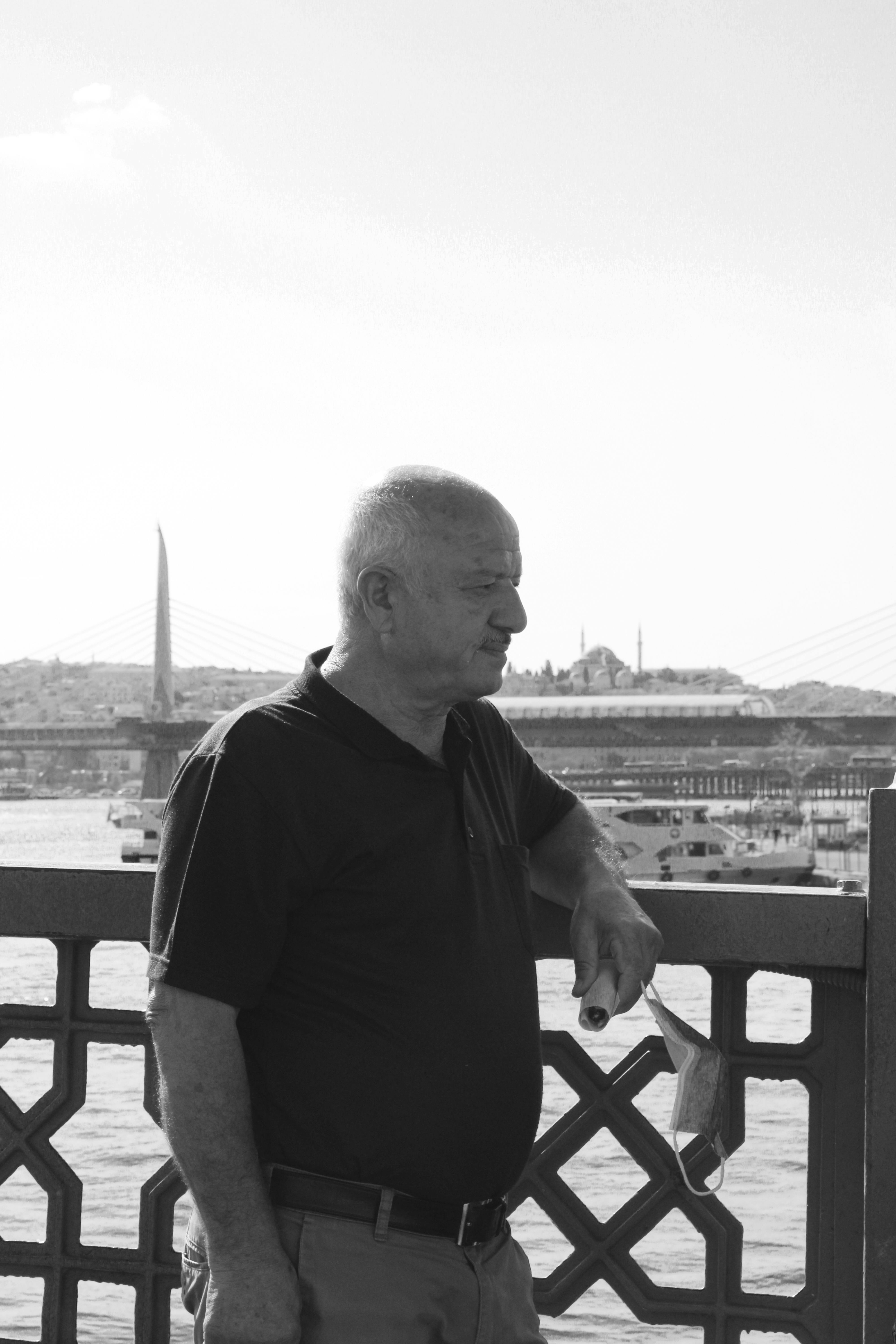 Grayscale Photo of a Man Standing Beside a Railing · Free Stock Photo