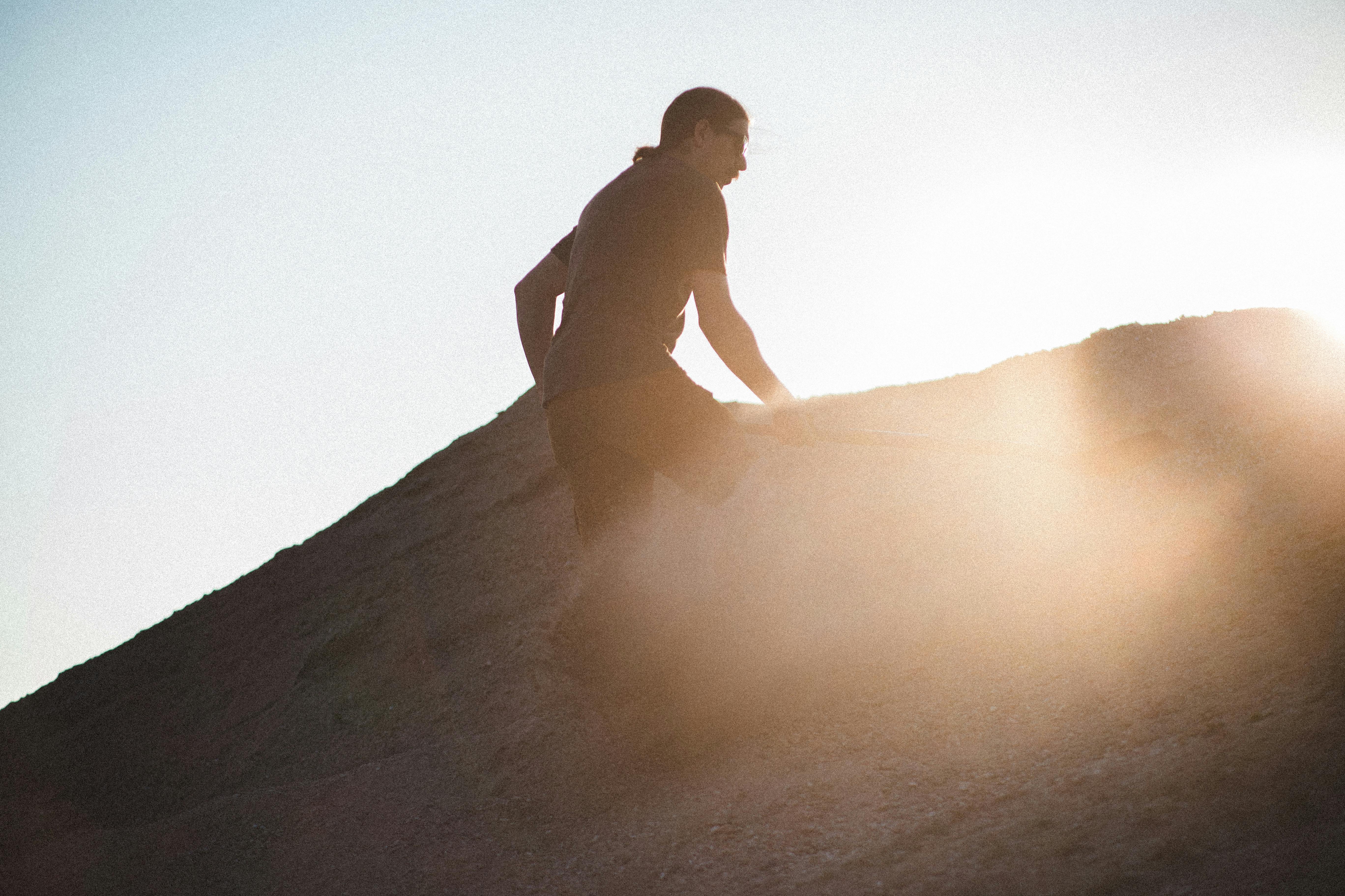 Back Lit Photograph of a Man Shoveling Sand · Free Stock Photo