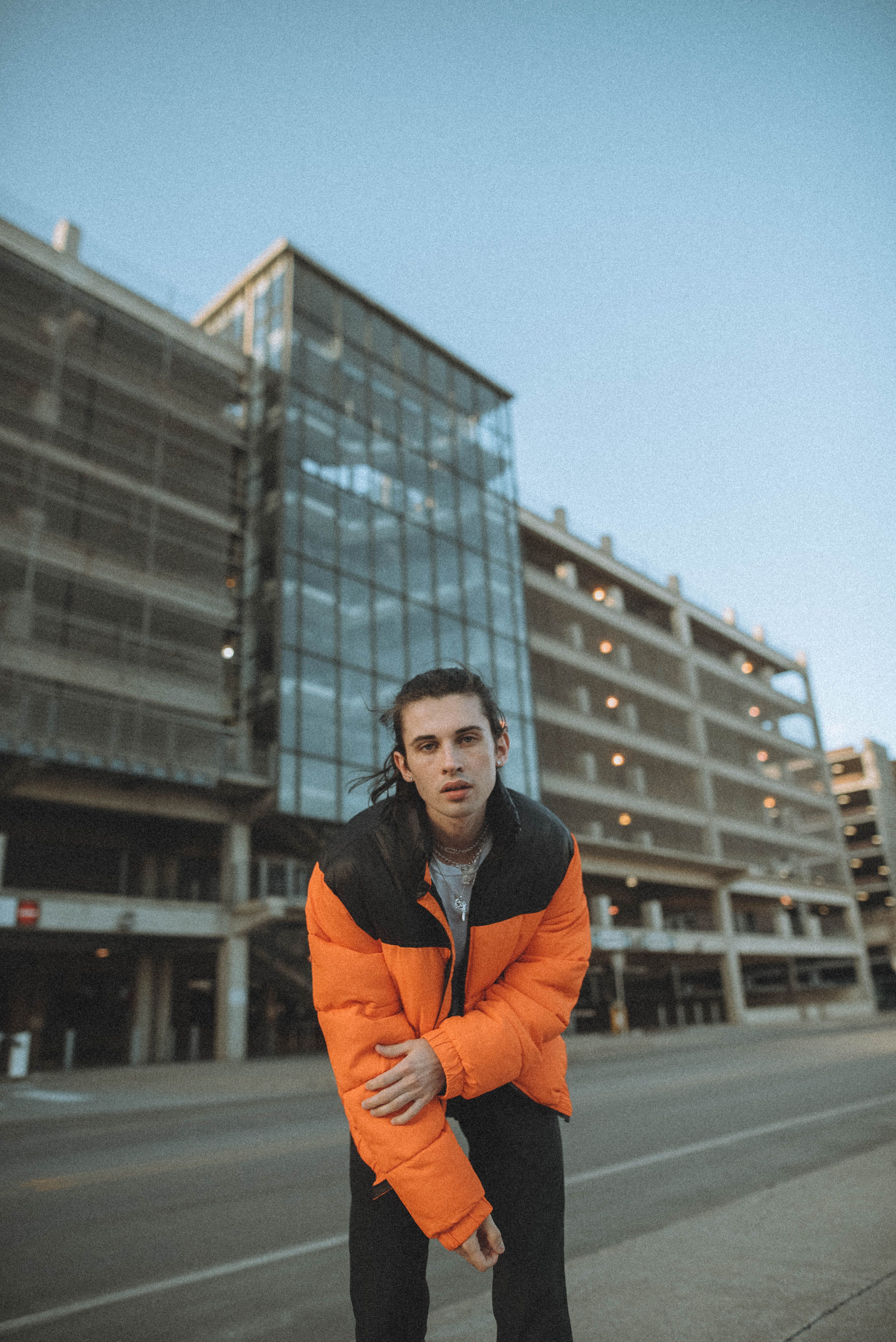 A Man Wearing Orange Jacket Standing on the Street NEar the Building ...