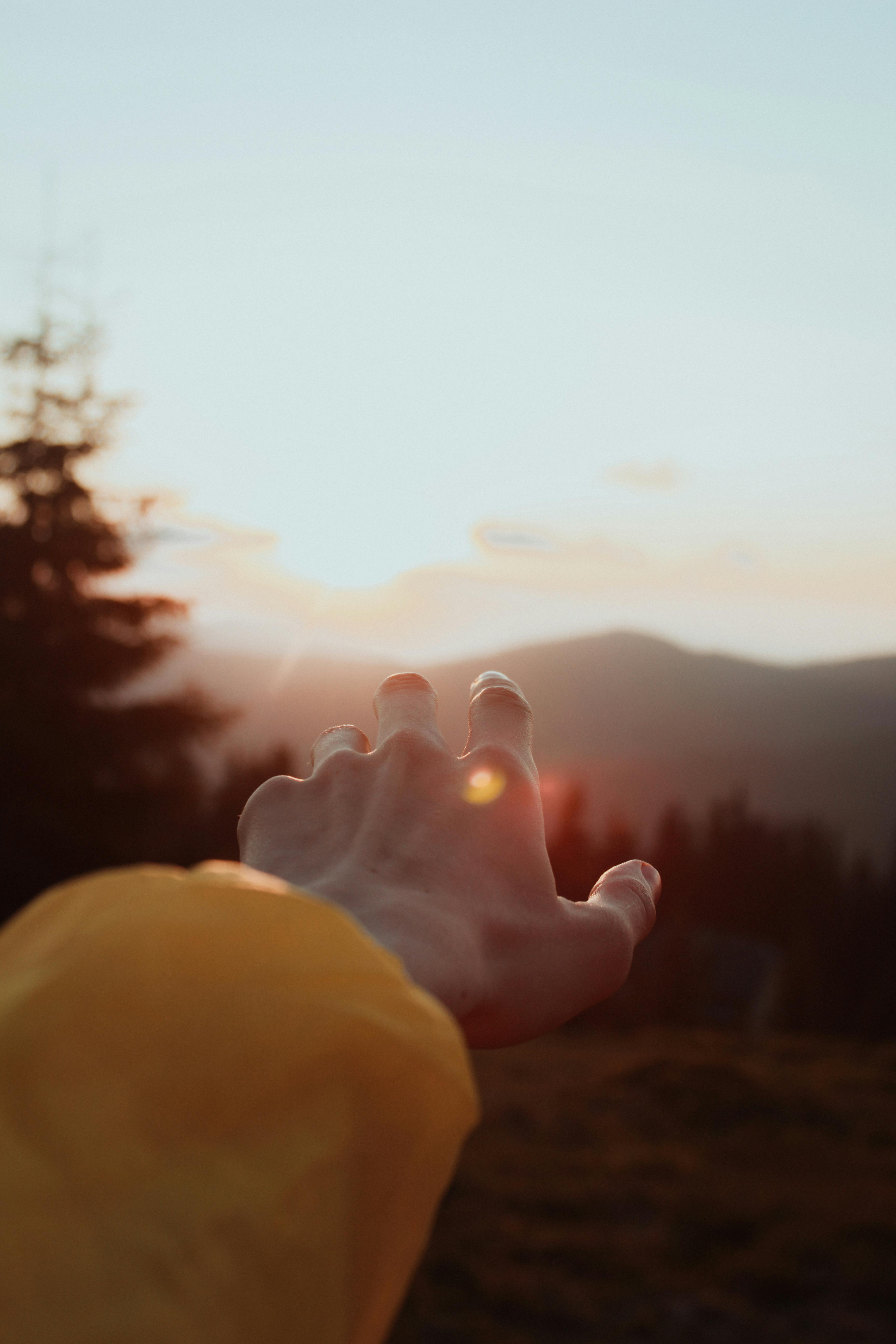 Person Hand Stretching in Mountains on Sunset · Free Stock Photo