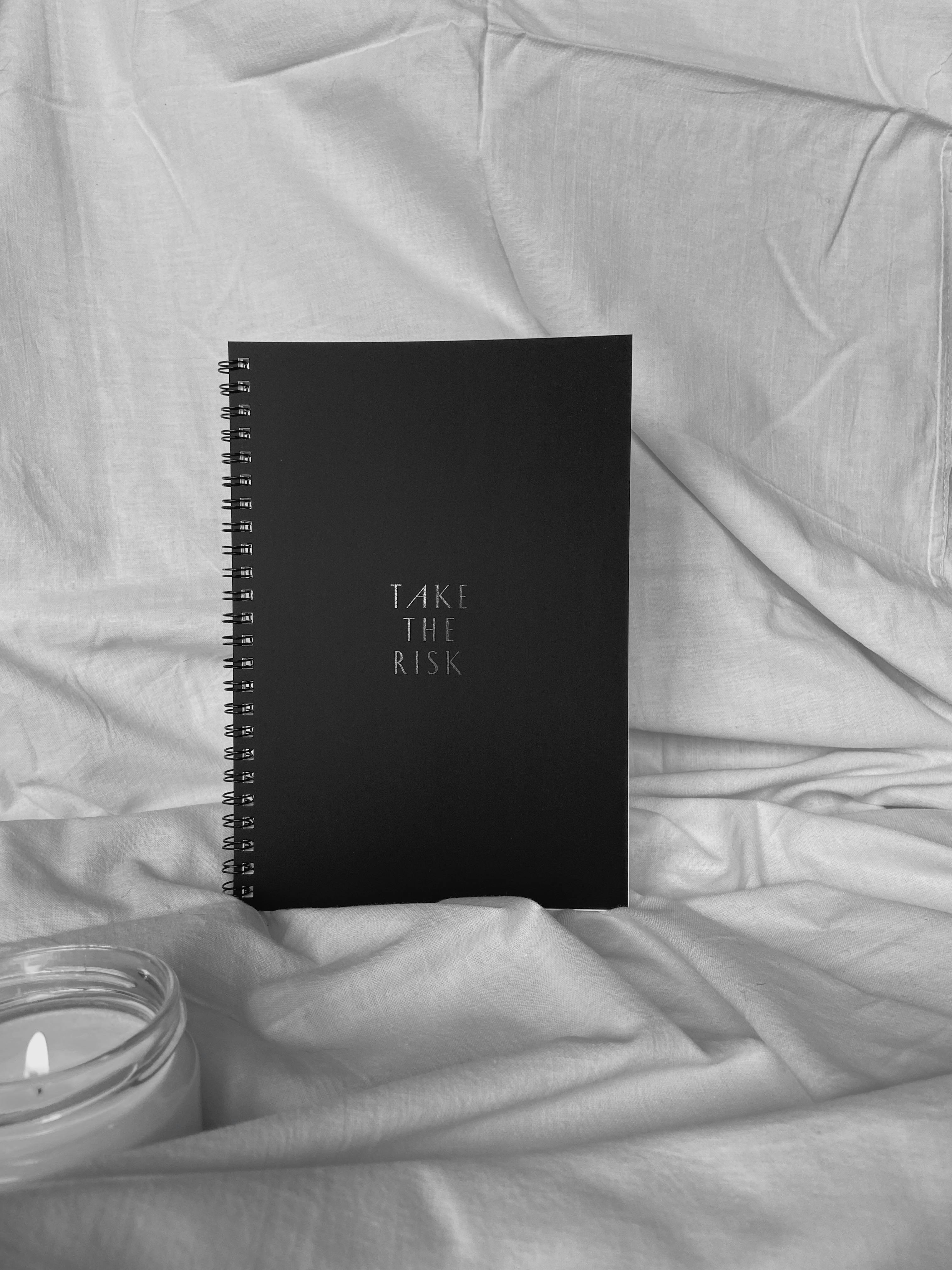 A Grayscale of Spiral Notebooks beside a Lighted Candle · Free Stock Photo