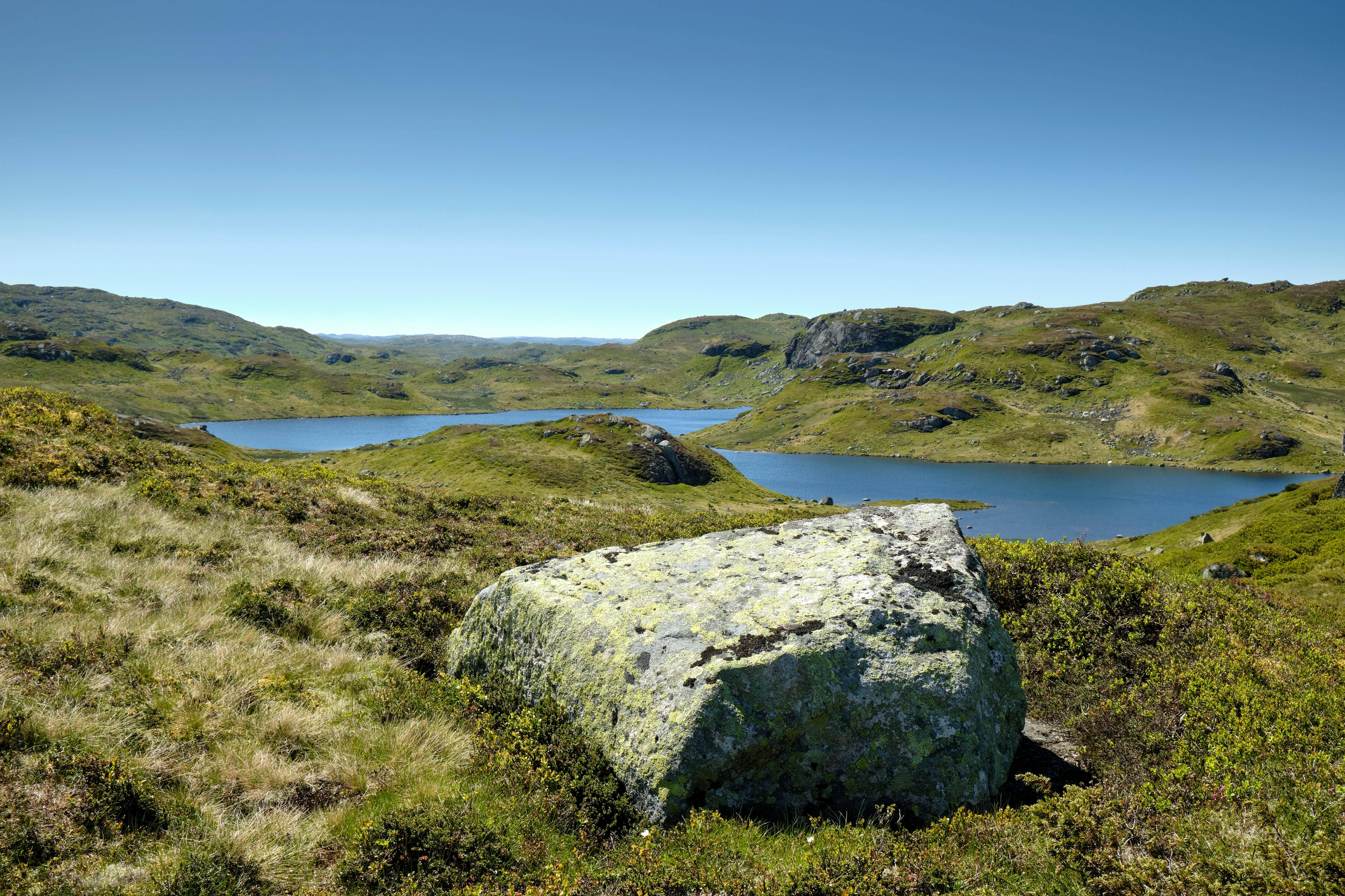 A Big Rock on a Grassland with a Lake · Free Stock Photo