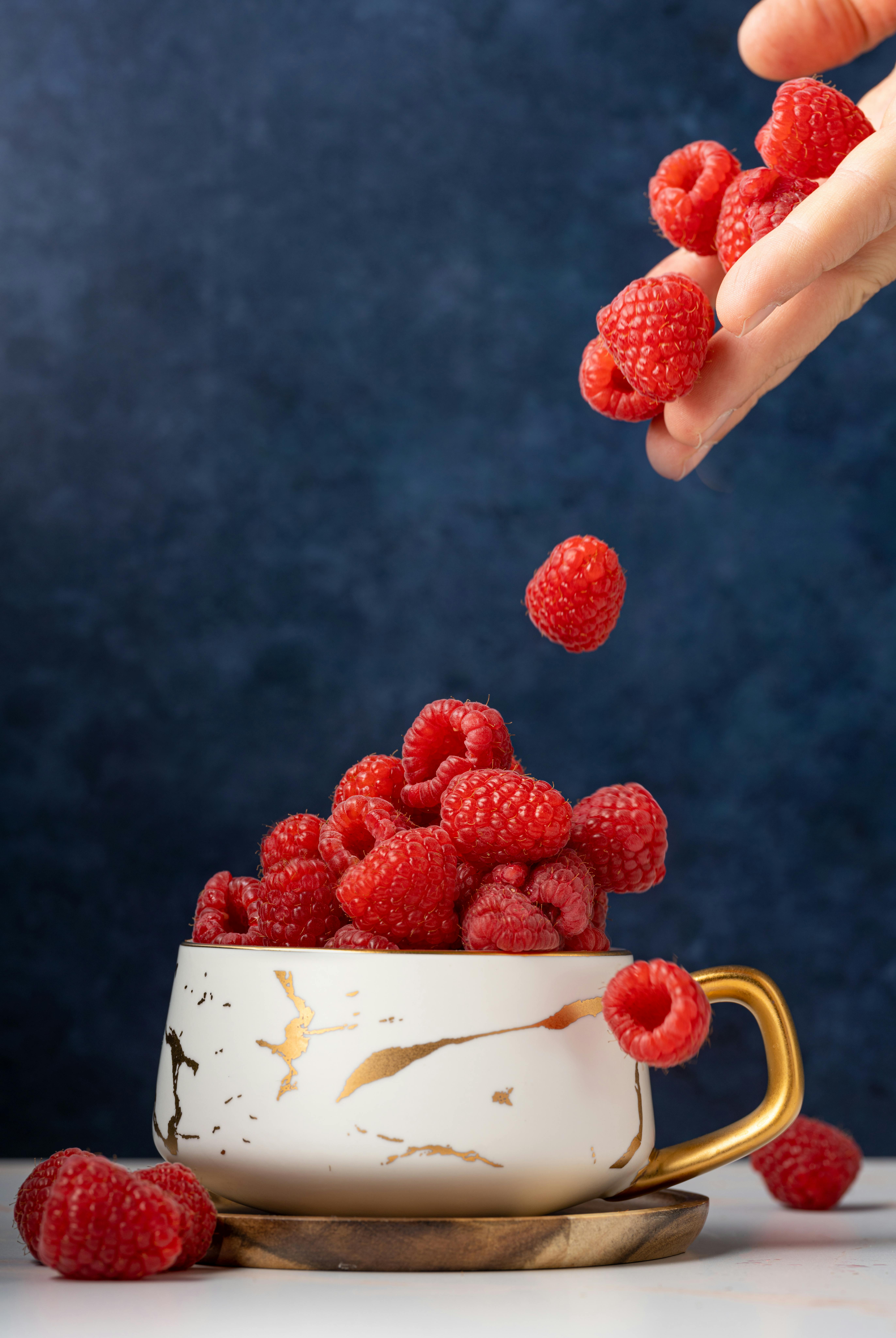 Person Hand Throwing Raspberries into Cup · Free Stock Photo