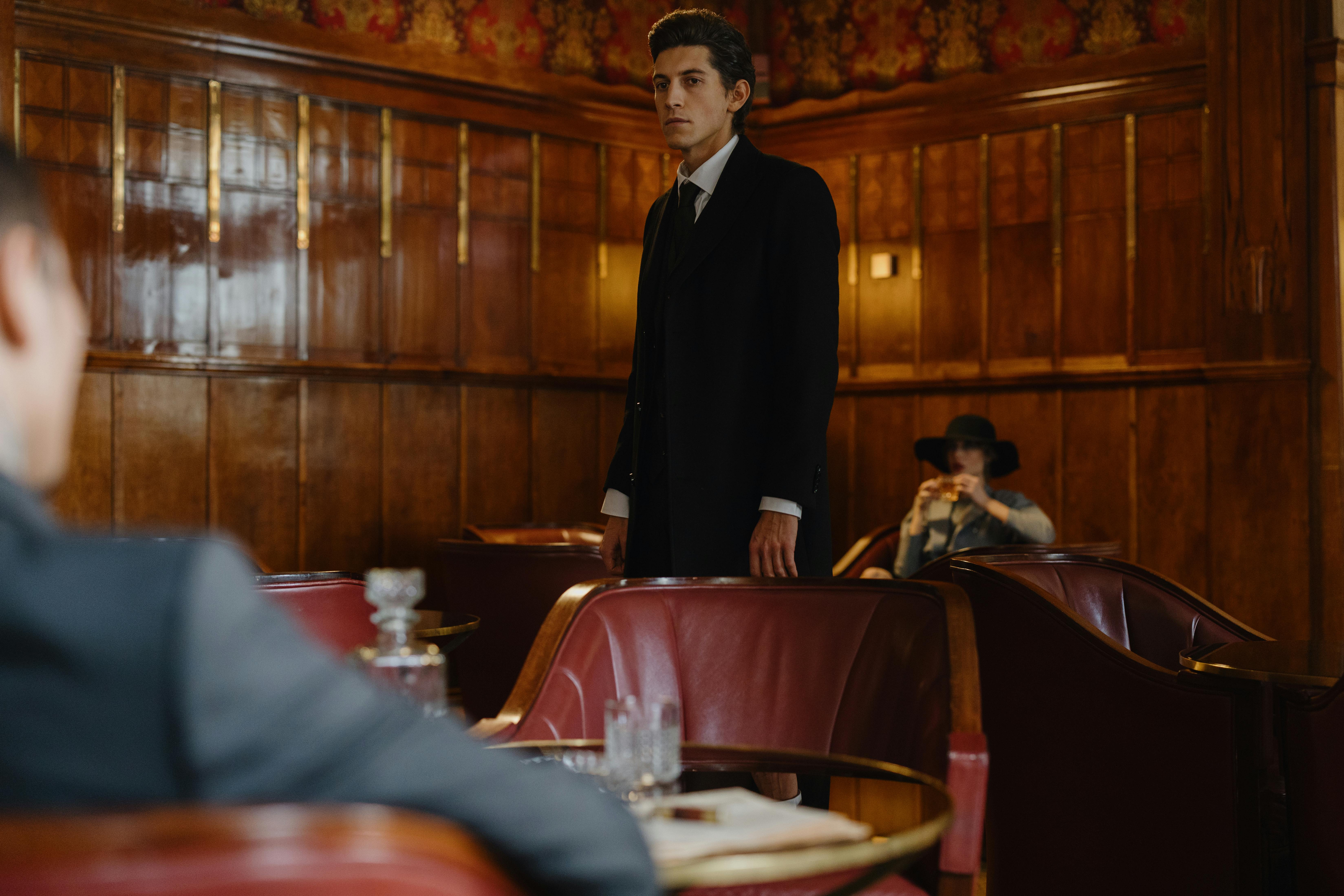 Man in Black Suit Standing Behind a Chair · Free Stock Photo