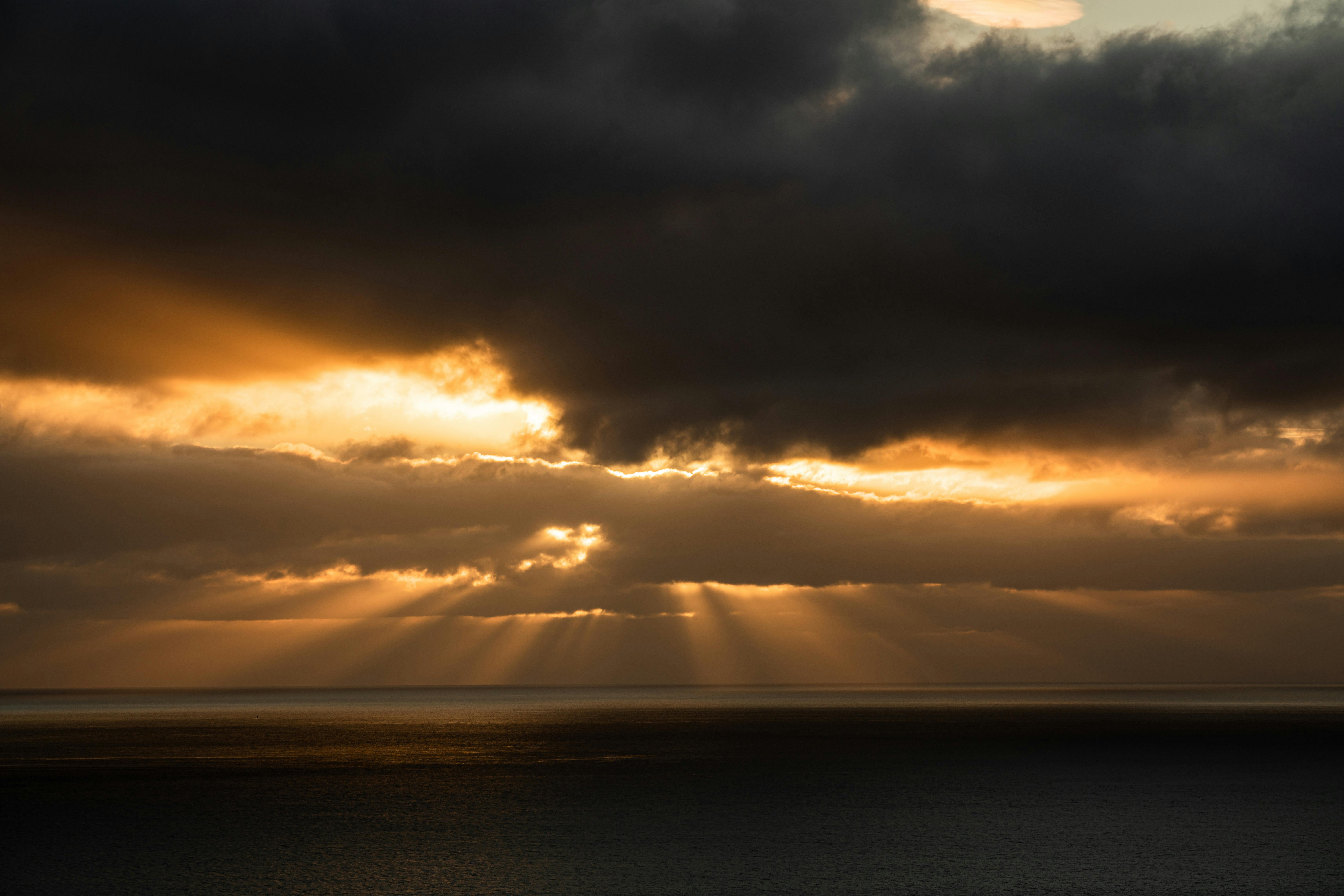 The Sun Beaming Lightly in the Sea Under Cloudy Sky · Free Stock Photo