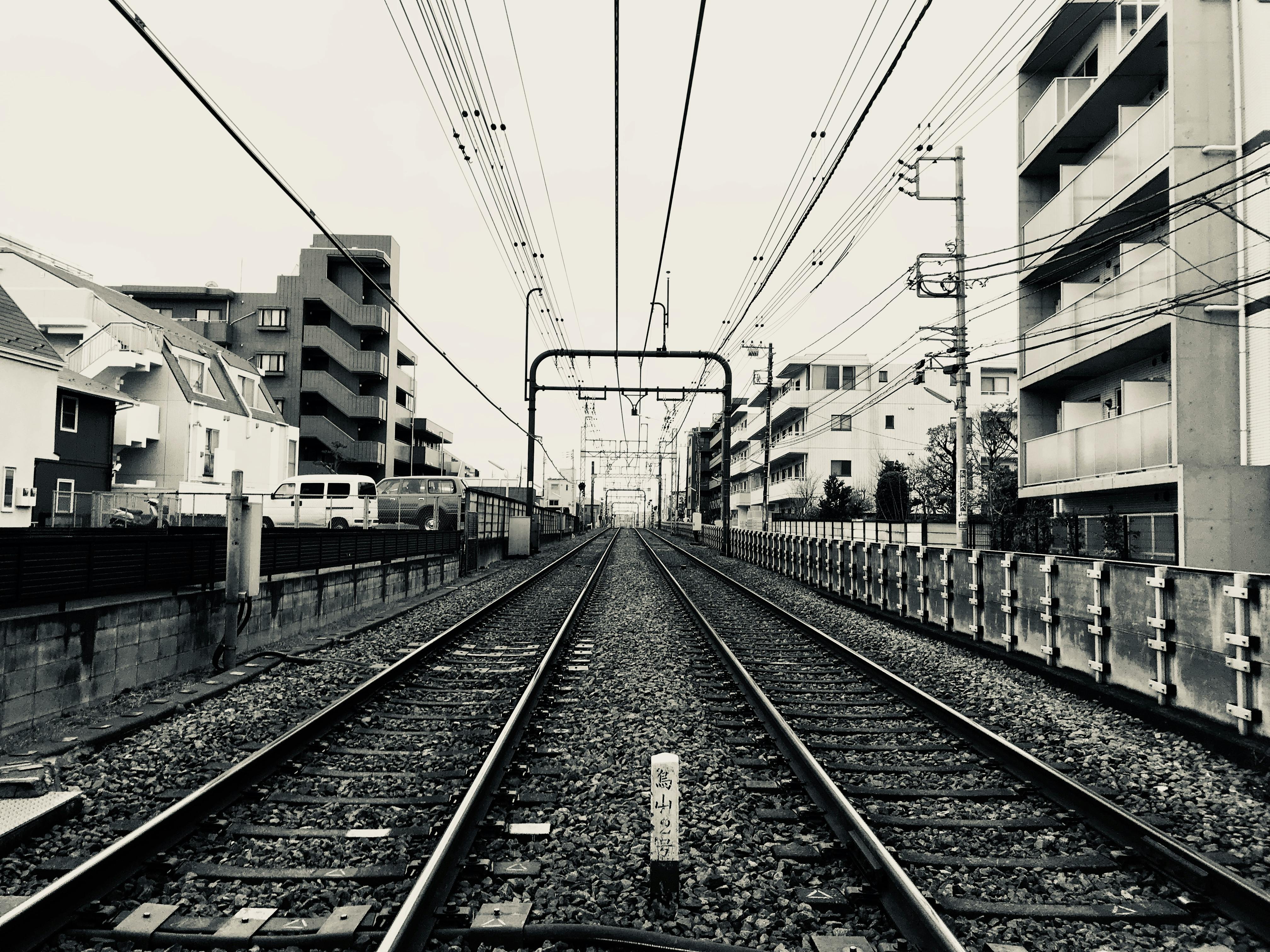 Grayscale Photography of Train Rail Between Buildings · Free Stock Photo Grayscale Photography of Train Rail Between Buildings · Free Stock Photo