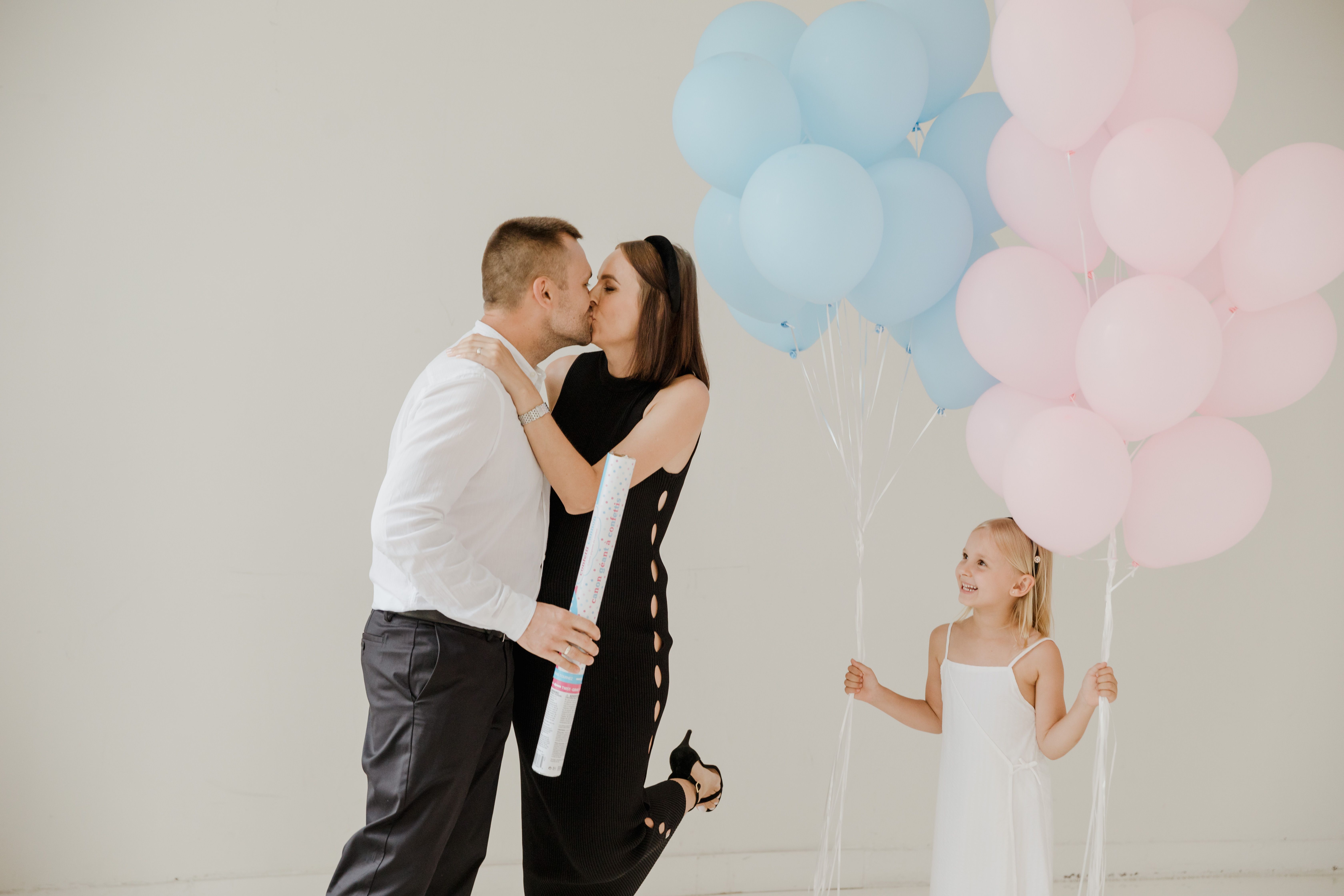 Couple Kissing while Holding their Child · Free Stock Photo