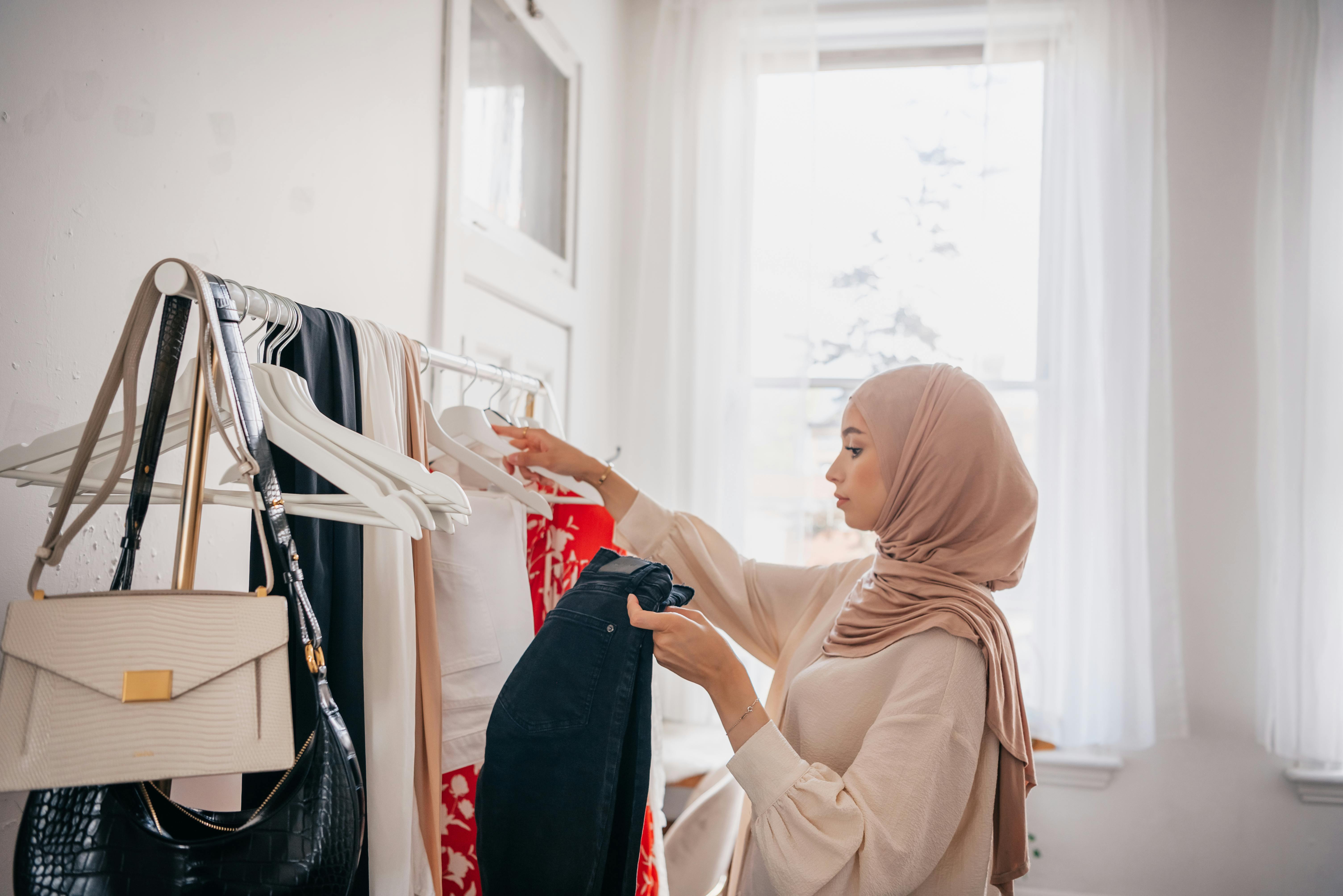 Woman Wearing Hijab Standing in Front of a Clothing Rack · Free Stock Photo