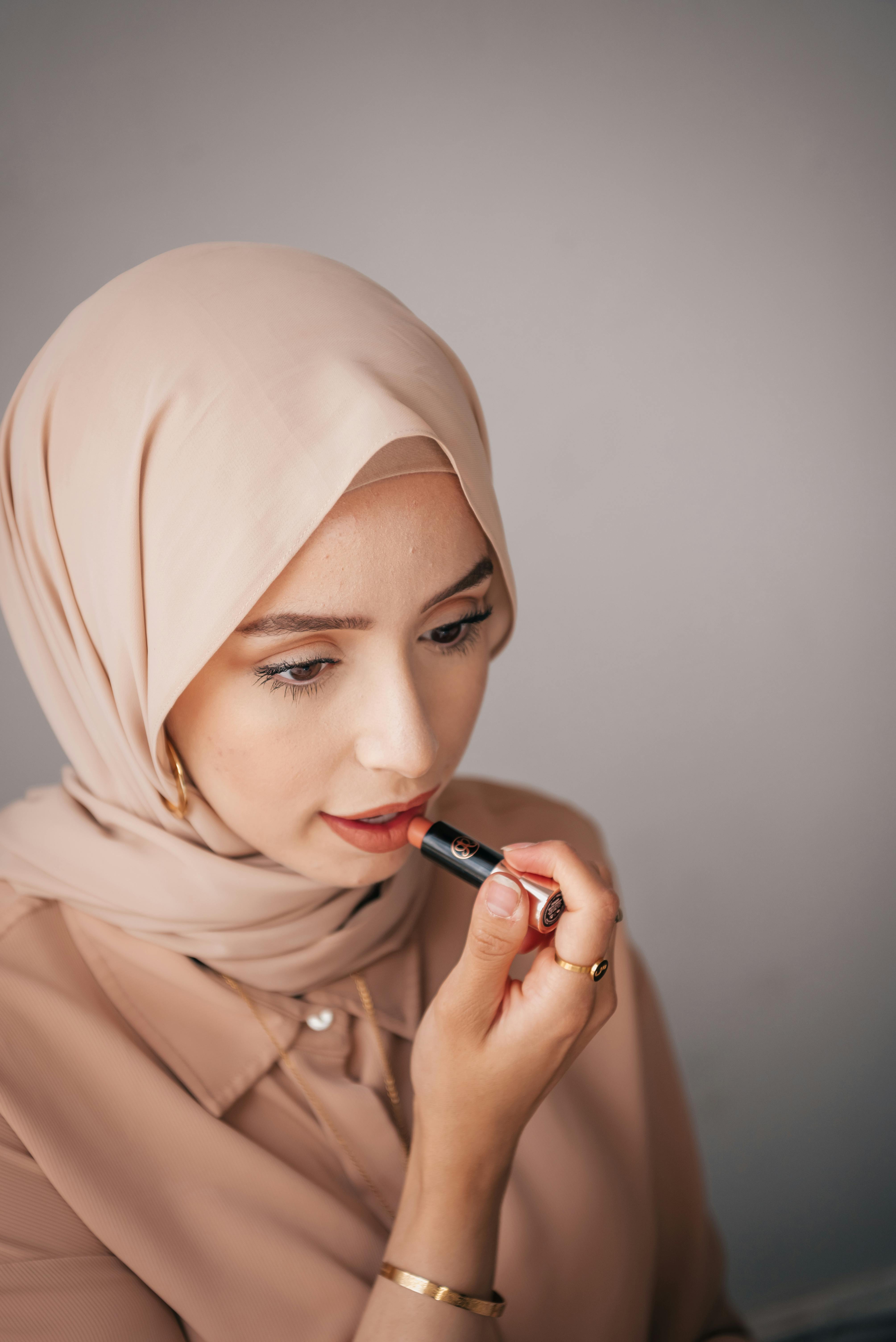 A Woman in White Hijab Applying Cosmetic on Her Lips · Free Stock Photo