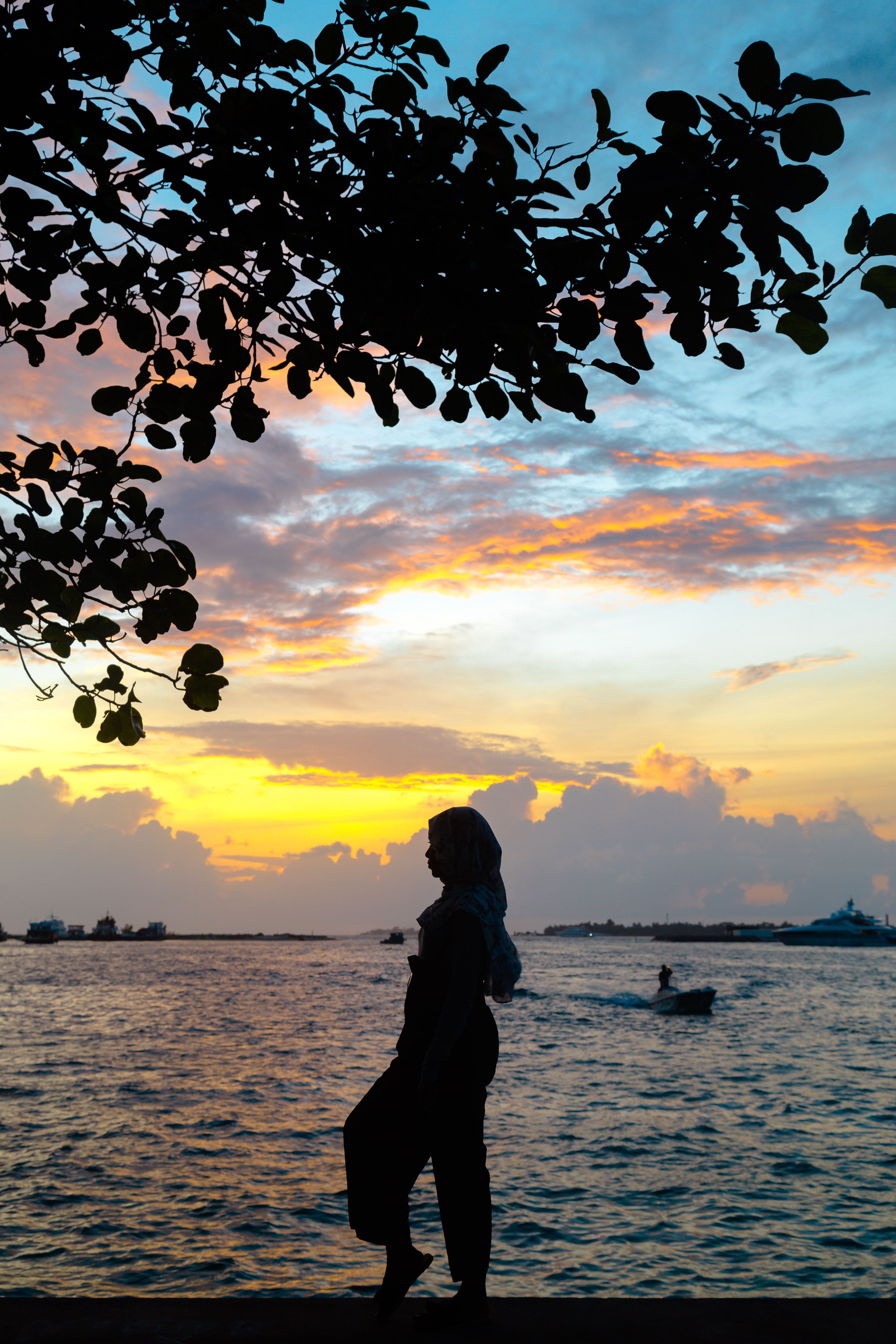 Silhouette of Woman Standing on Seashore during Sunset · Free Stock Photo