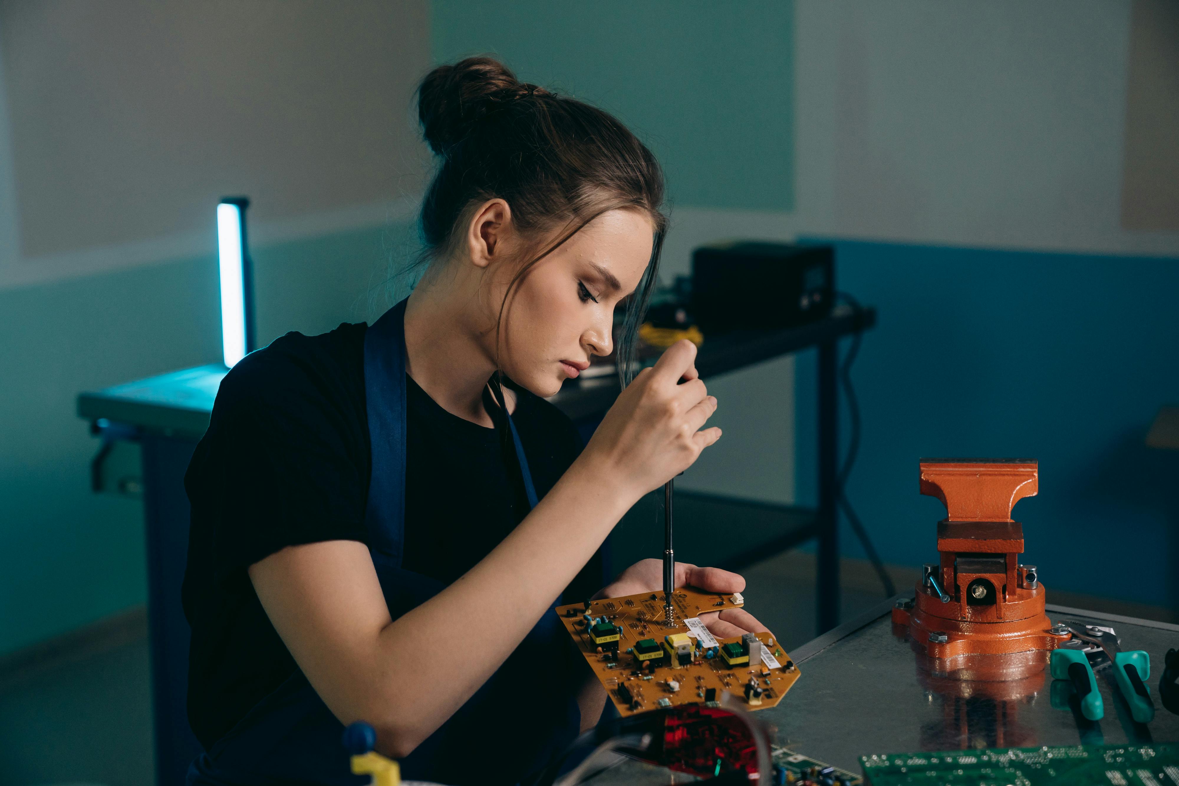 Woman Sitting and Working on Computer Hardware · Free Stock Photo