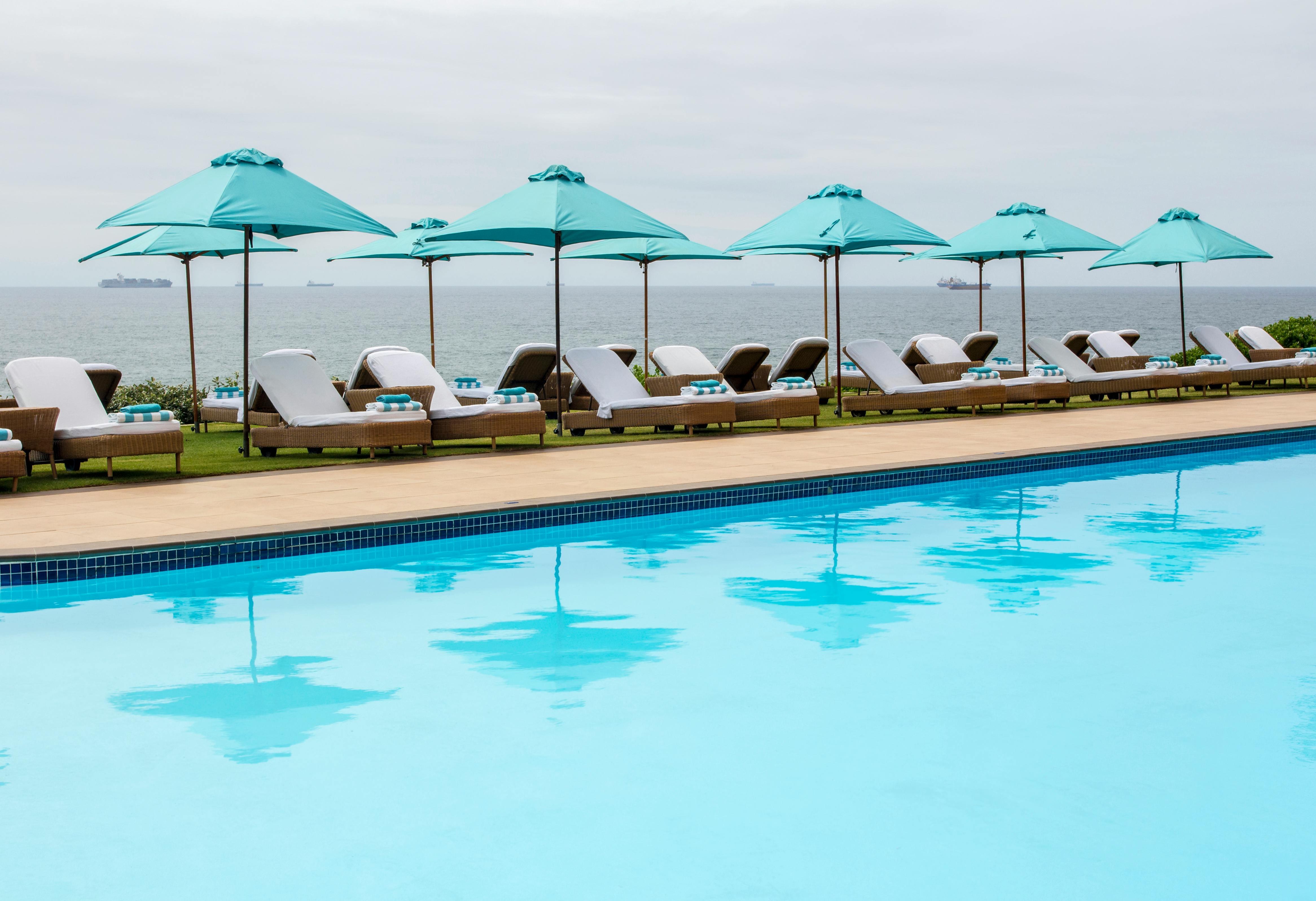 Poolside with Beach Umbrellas and Lounge Chairs Beside Concrete Villas ...