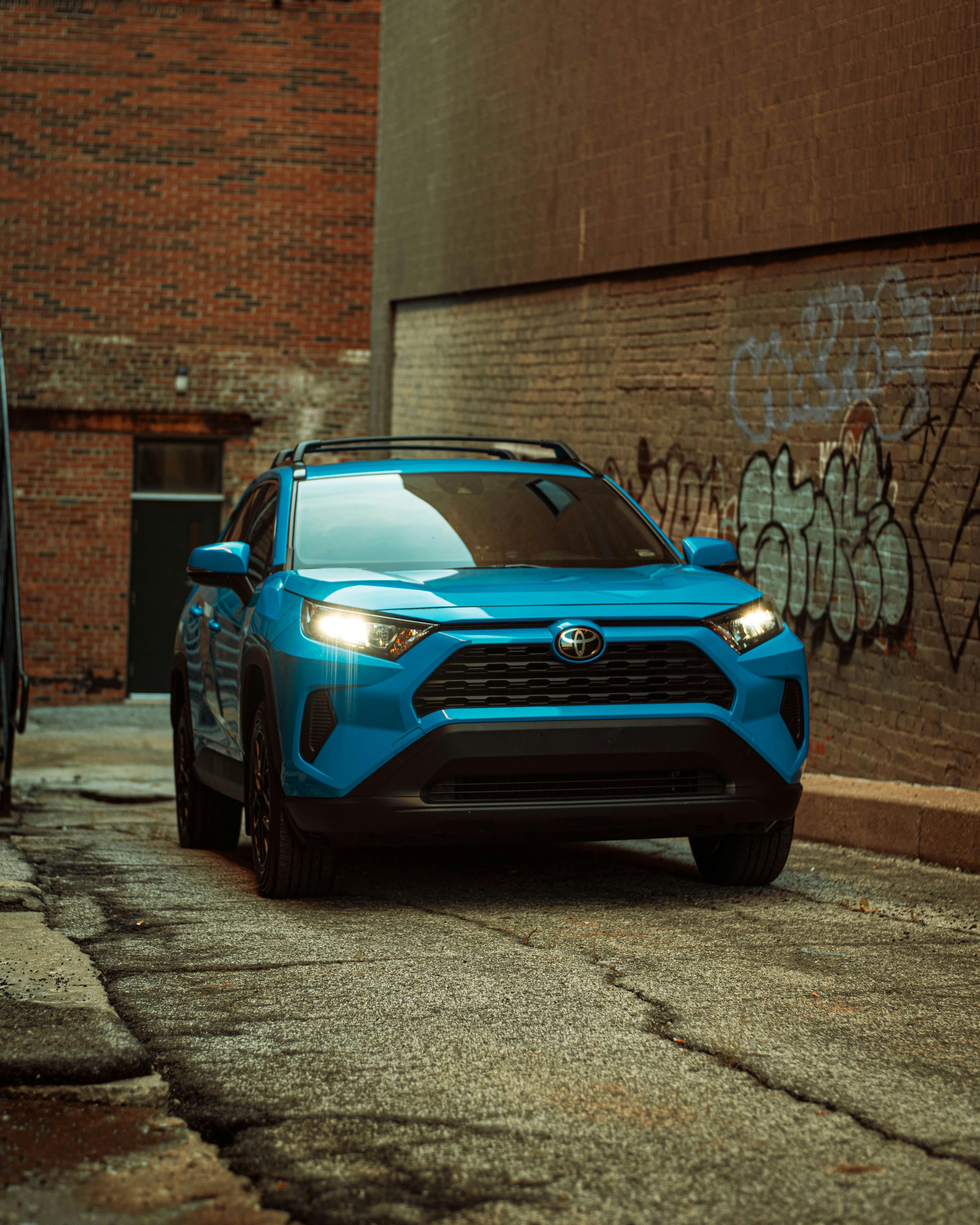 Blue Car Parked Beside Brown Brick Wall · Free Stock Photo