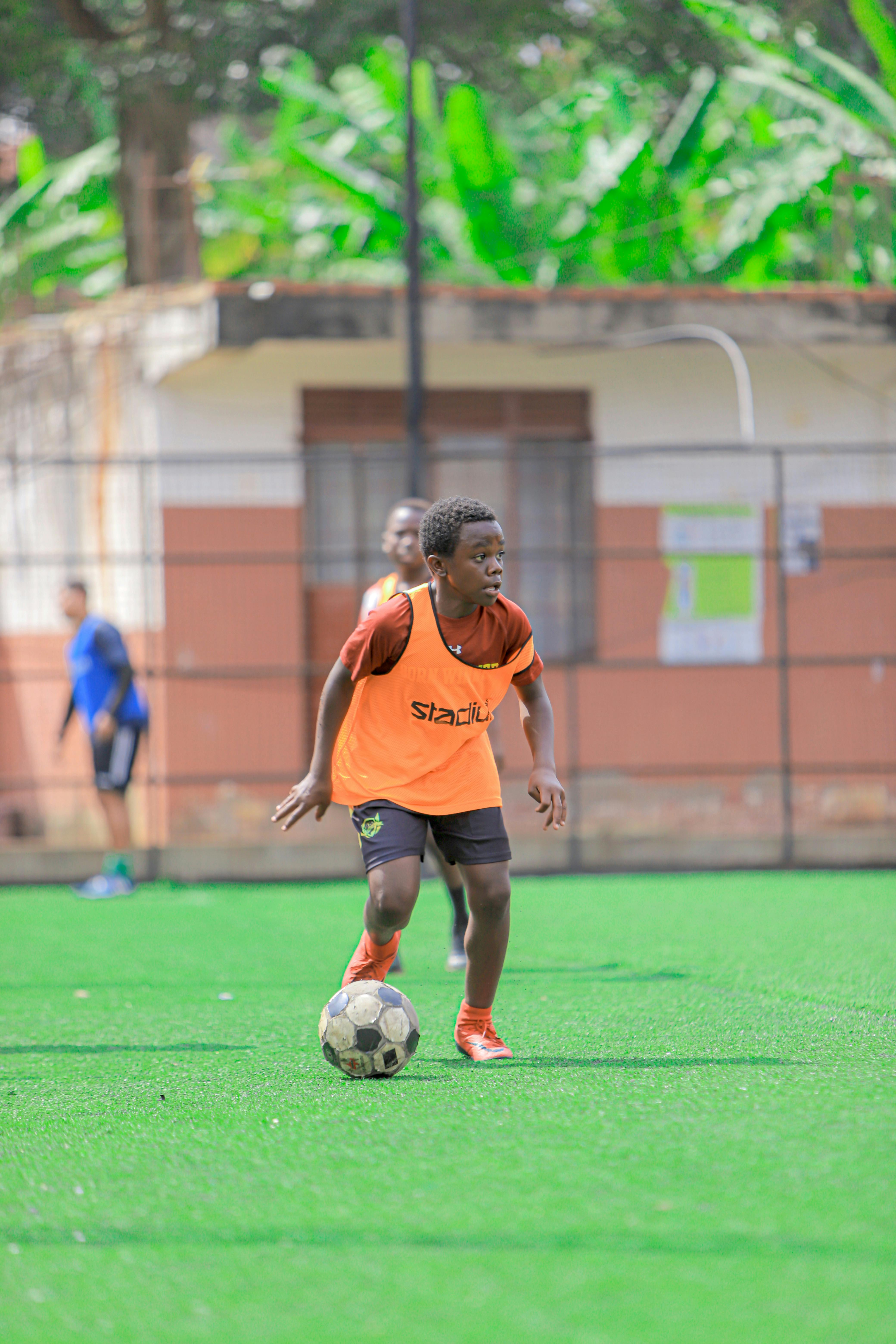 Boy in Football Shirt Walking on Pavement · Free Stock Photo
